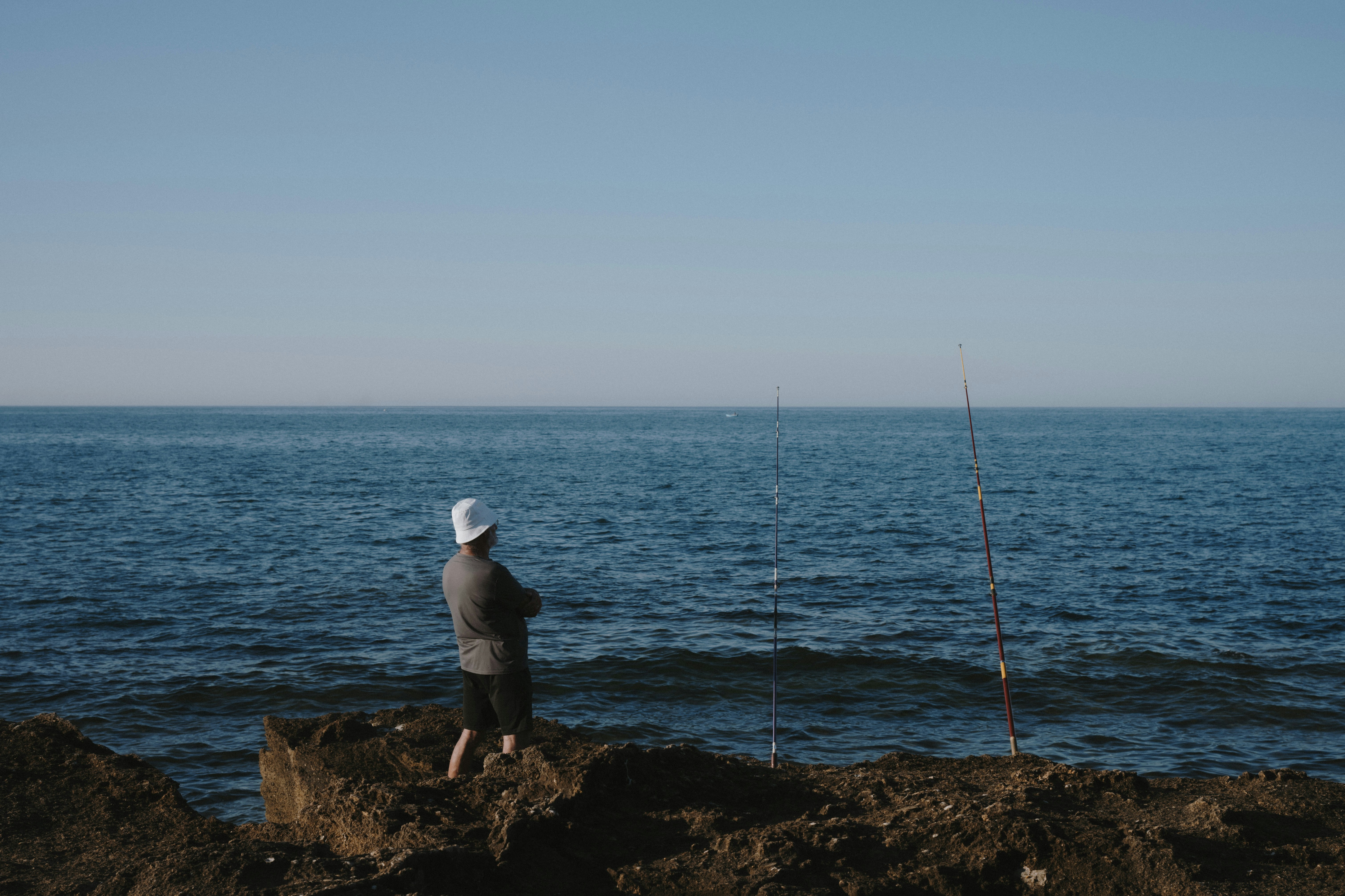 Rugged shoreline: a lone angler against the endless blue