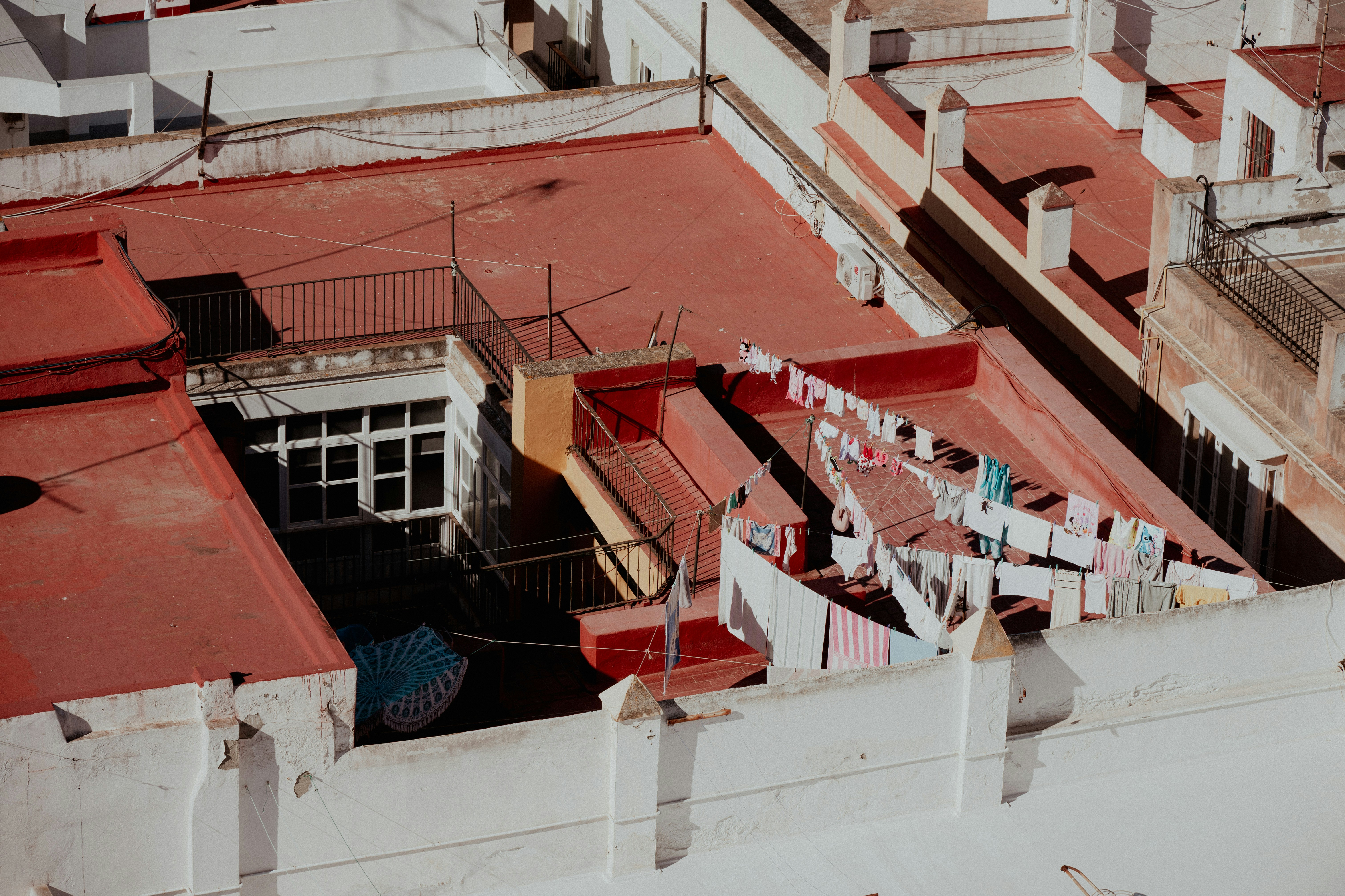 Laundry hanging on lines across a red rooftop terrace in a city