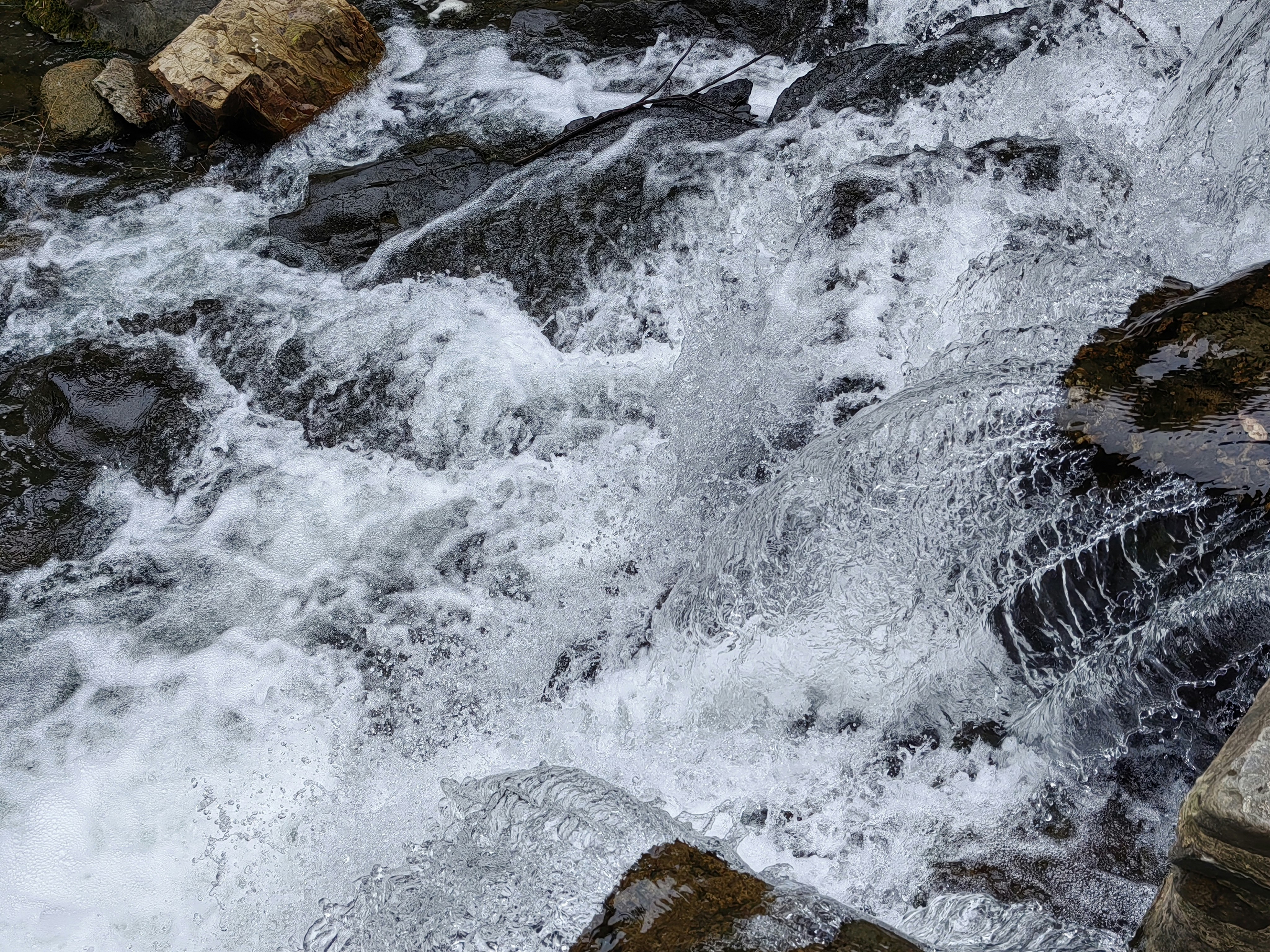White water cascading over dark wet rocks in a mountain stream