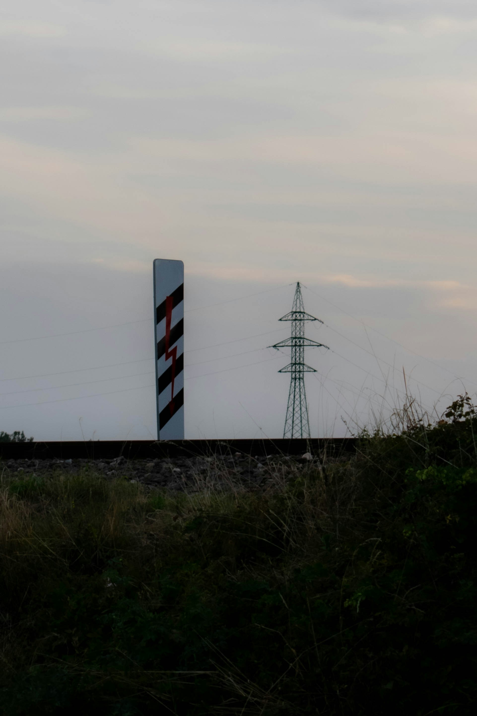 Railside Silhouette: A Tower and Power Lines Against a Quiet Sky