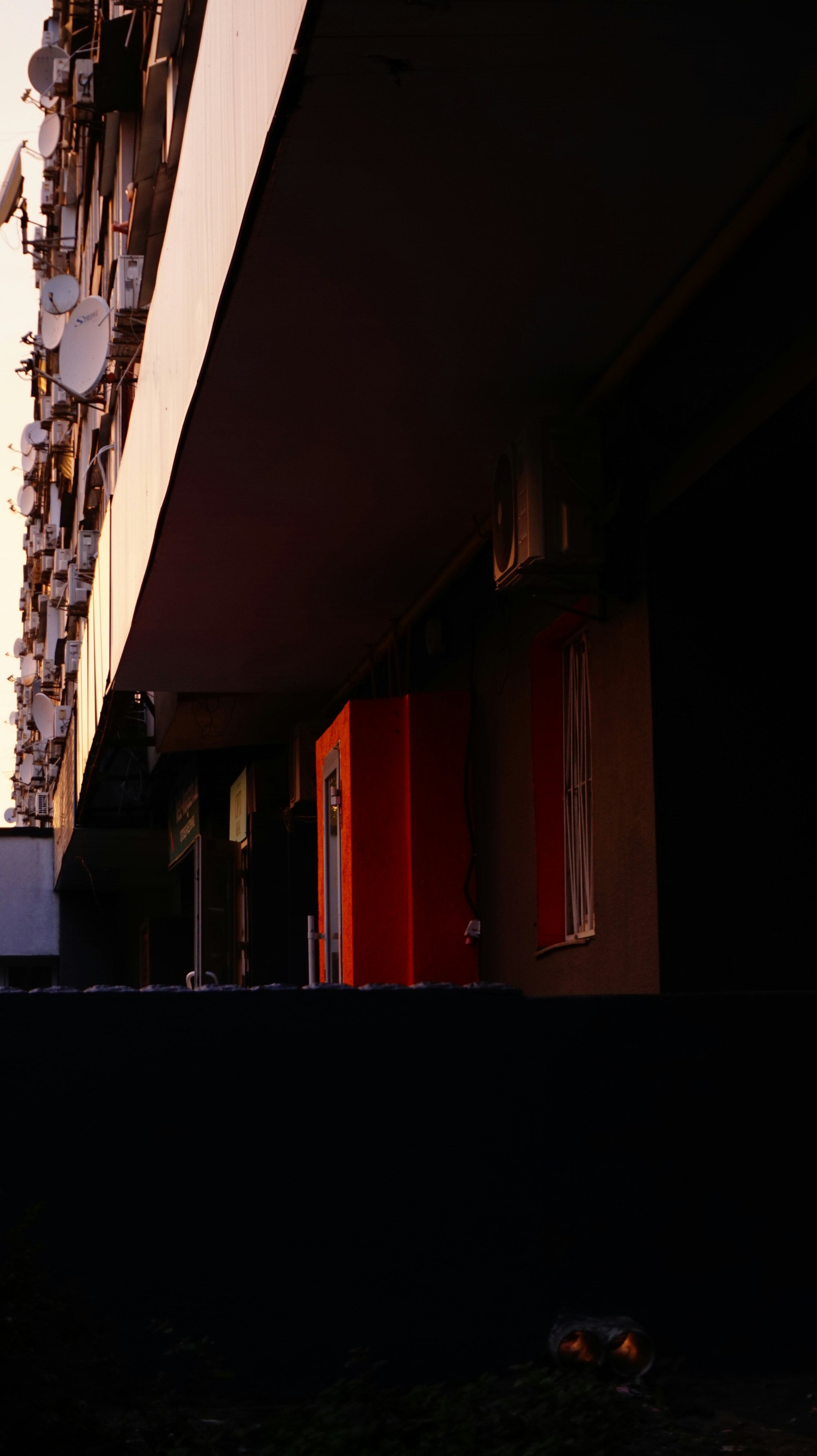 Urban Facade at Dusk: A Corridor of Dishes and Shadow