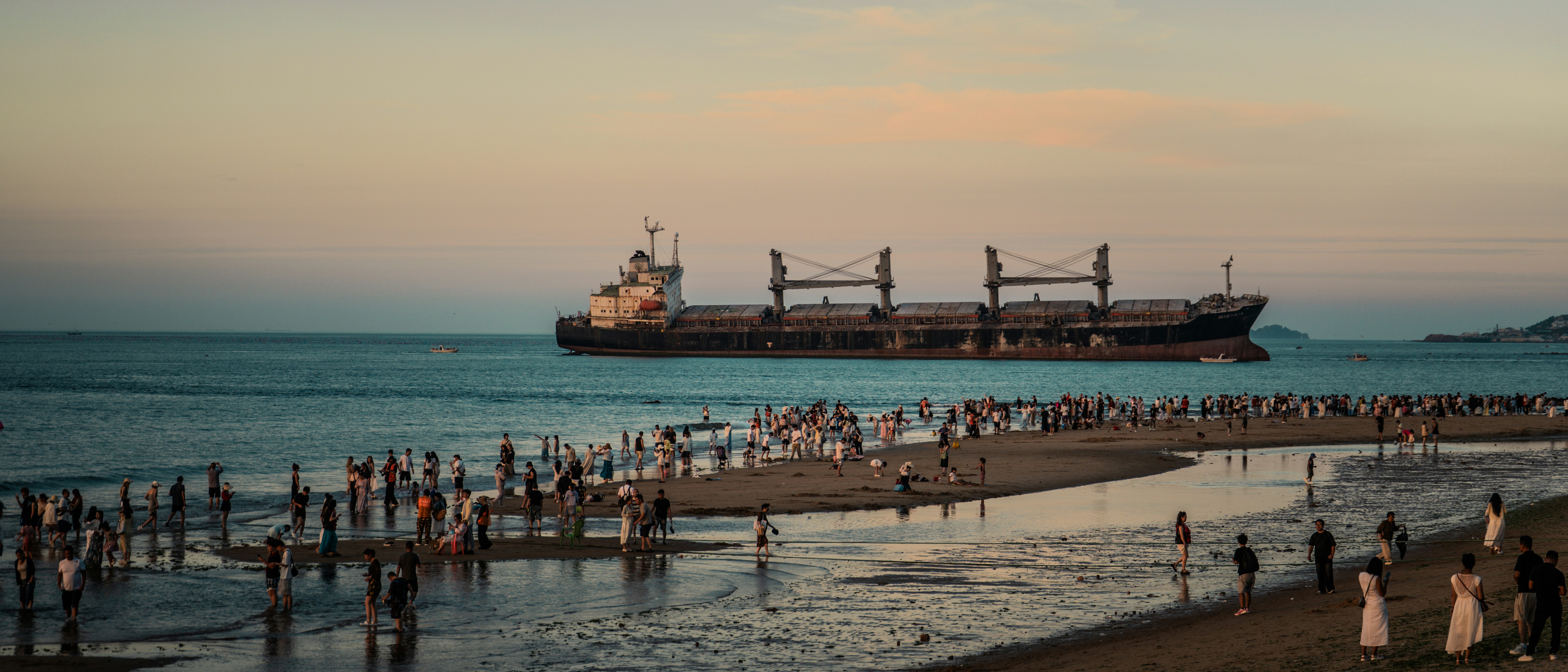 Harbor Crowd and Cargo Vessel at Dusk