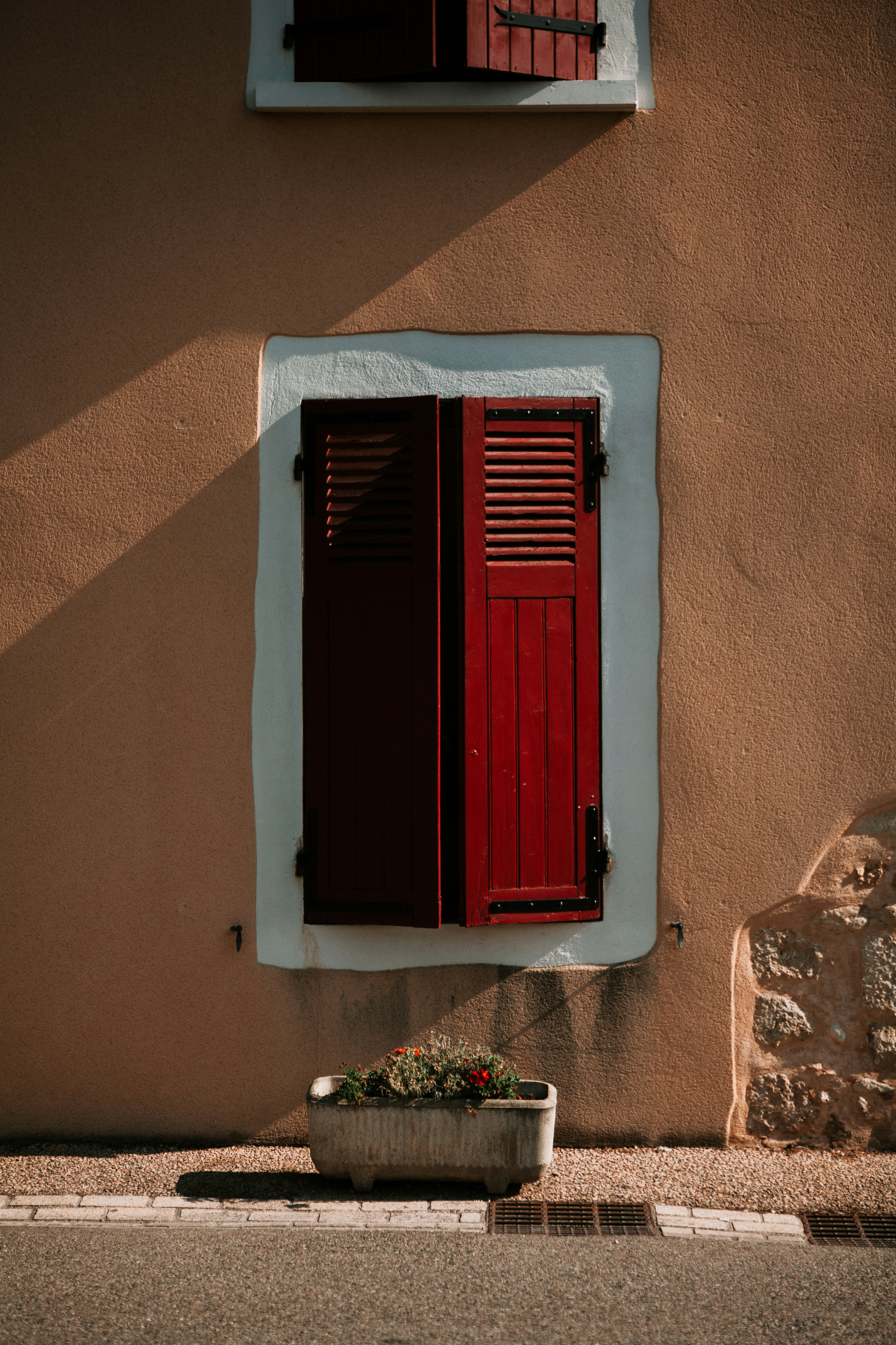 Sunlit Red Shutter Door with Balcony Shadow