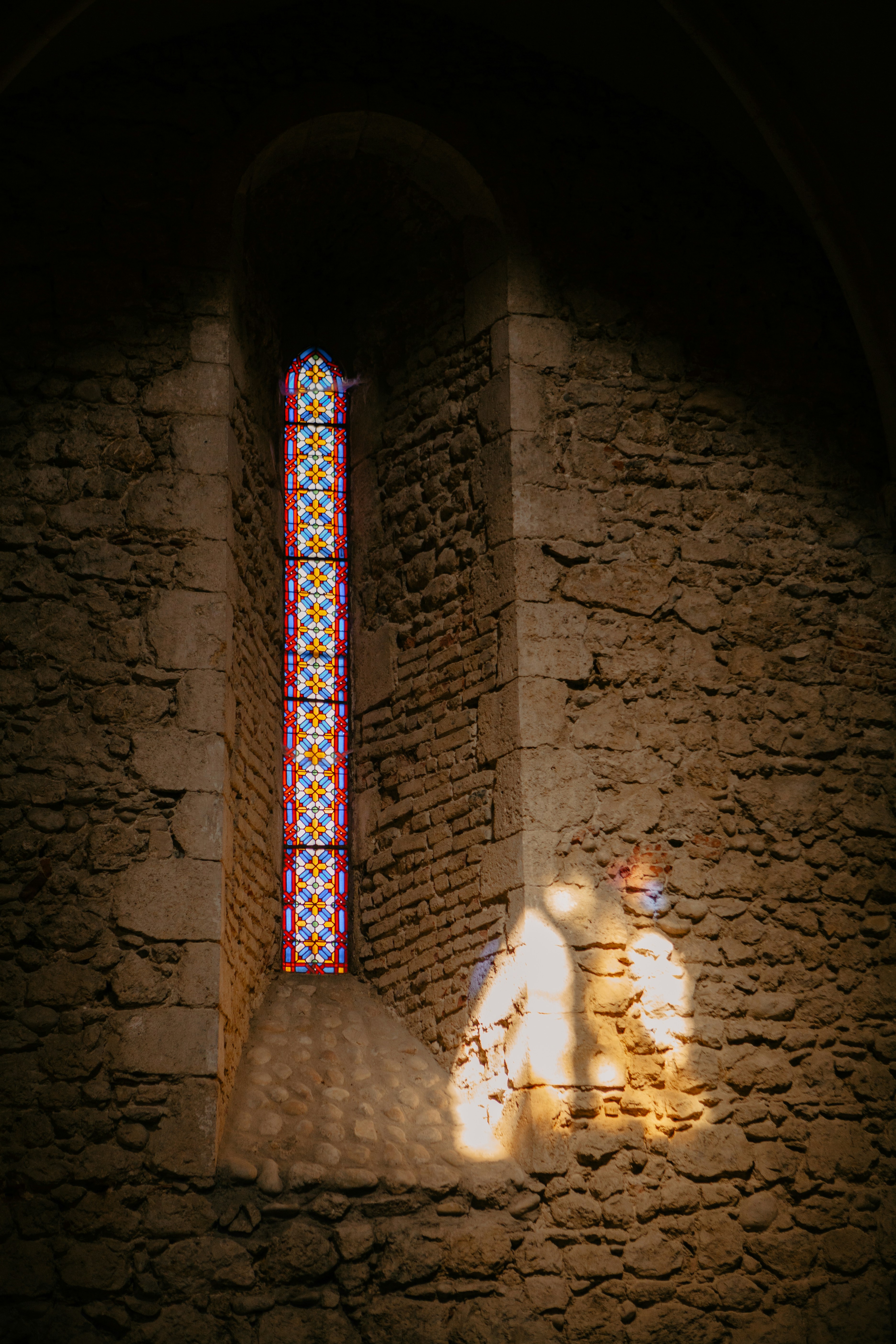 Stained Light Through Stone: A Chapel Window and Shadowed Wall