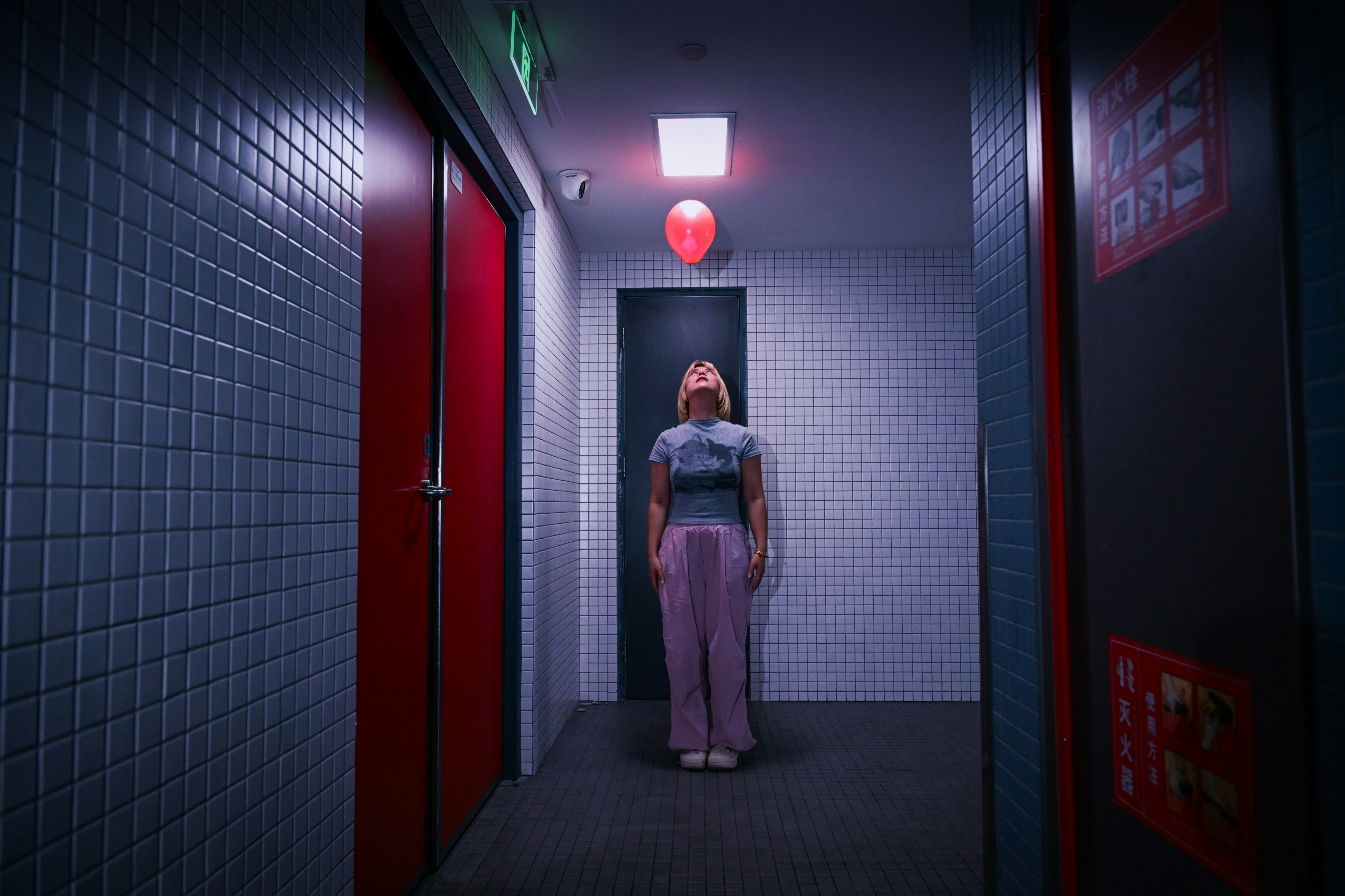 Balloon above a solitary figure in a dim hallway