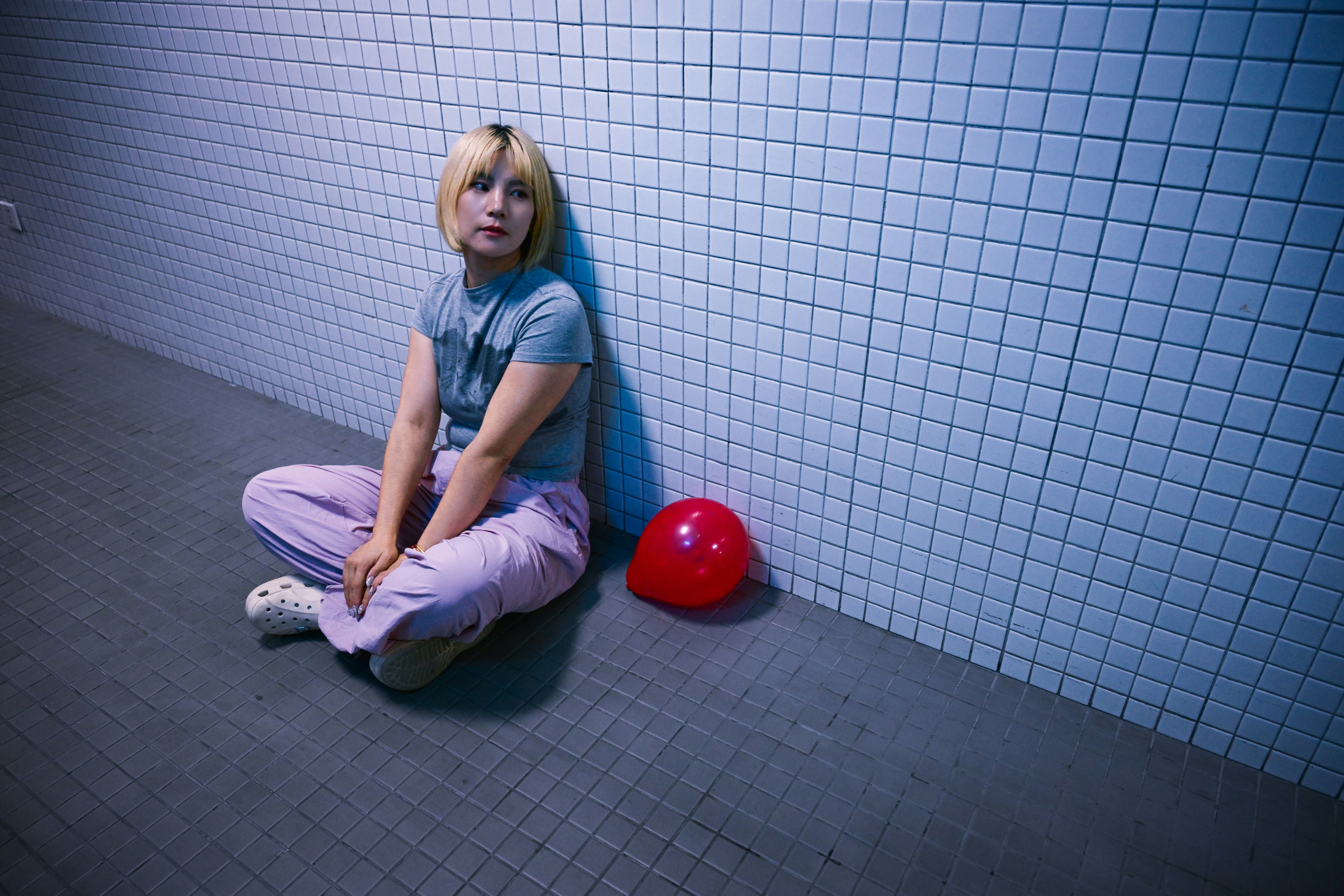 Blue-tinted Quiet: A Girl with a Red Balloon in an Empty Tile Corridor