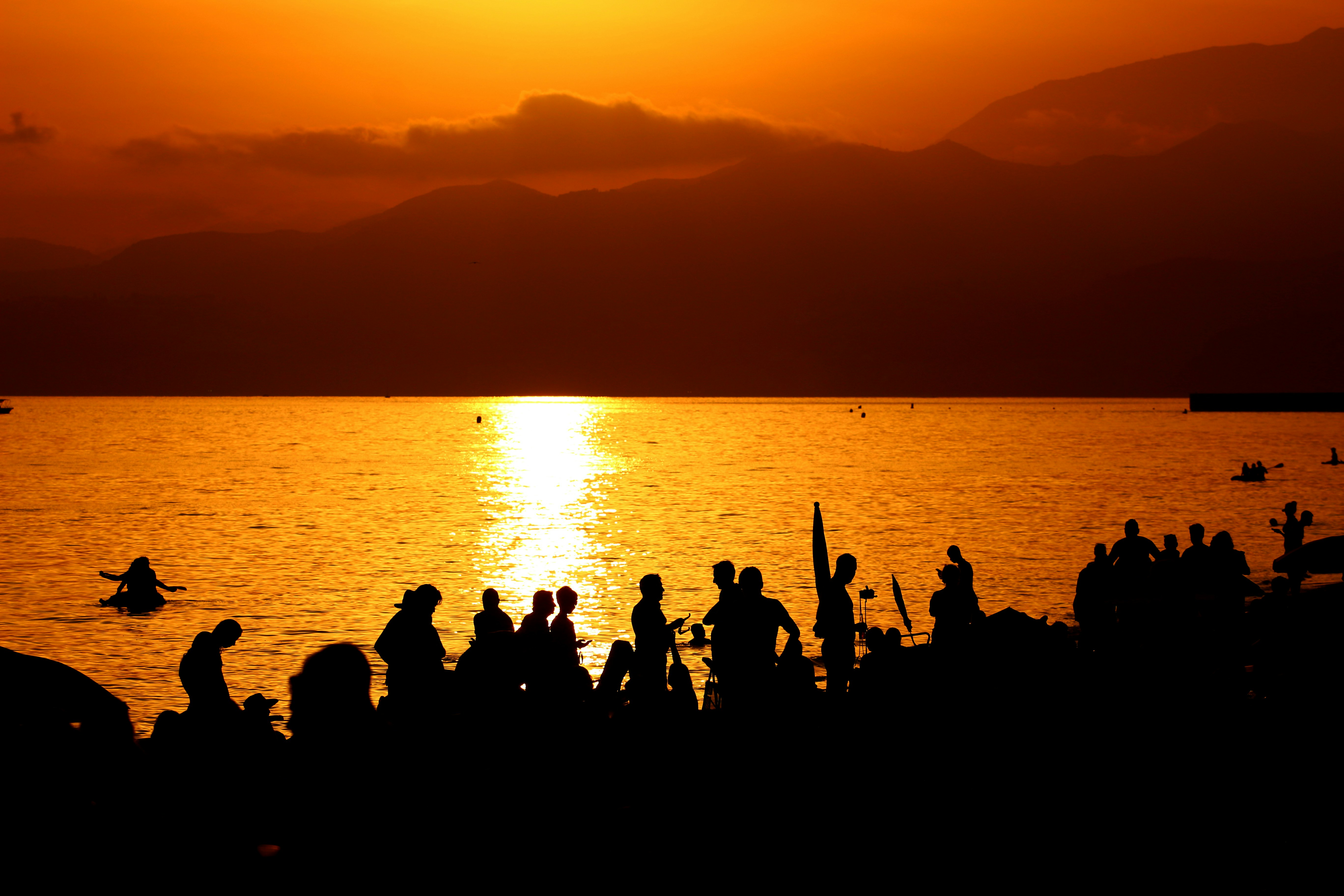 Golden Silhouettes at Dusk: A Crowded Shore Echoes the Sun