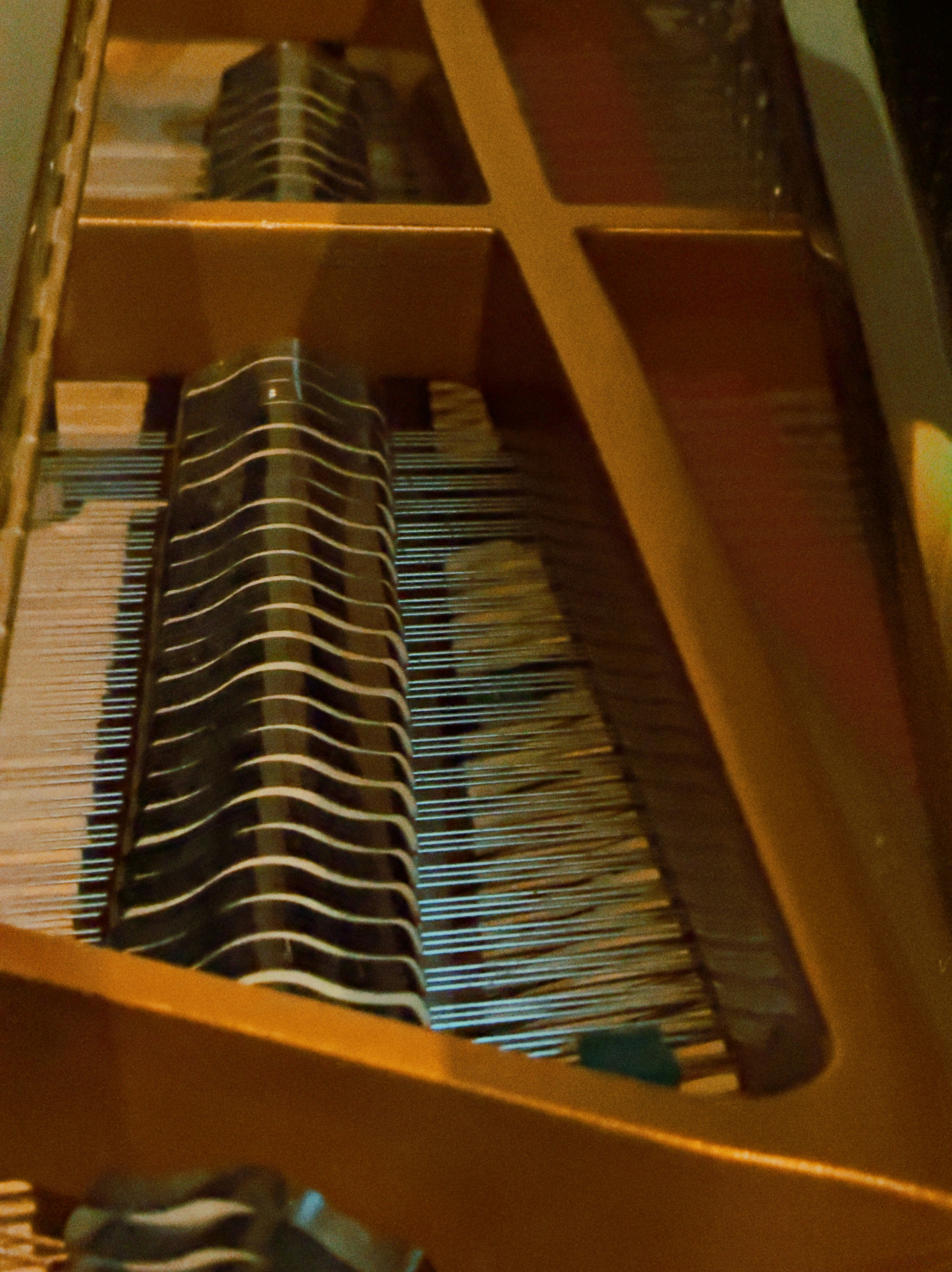 Industrial piano wiring: exposed strings under amber lighting