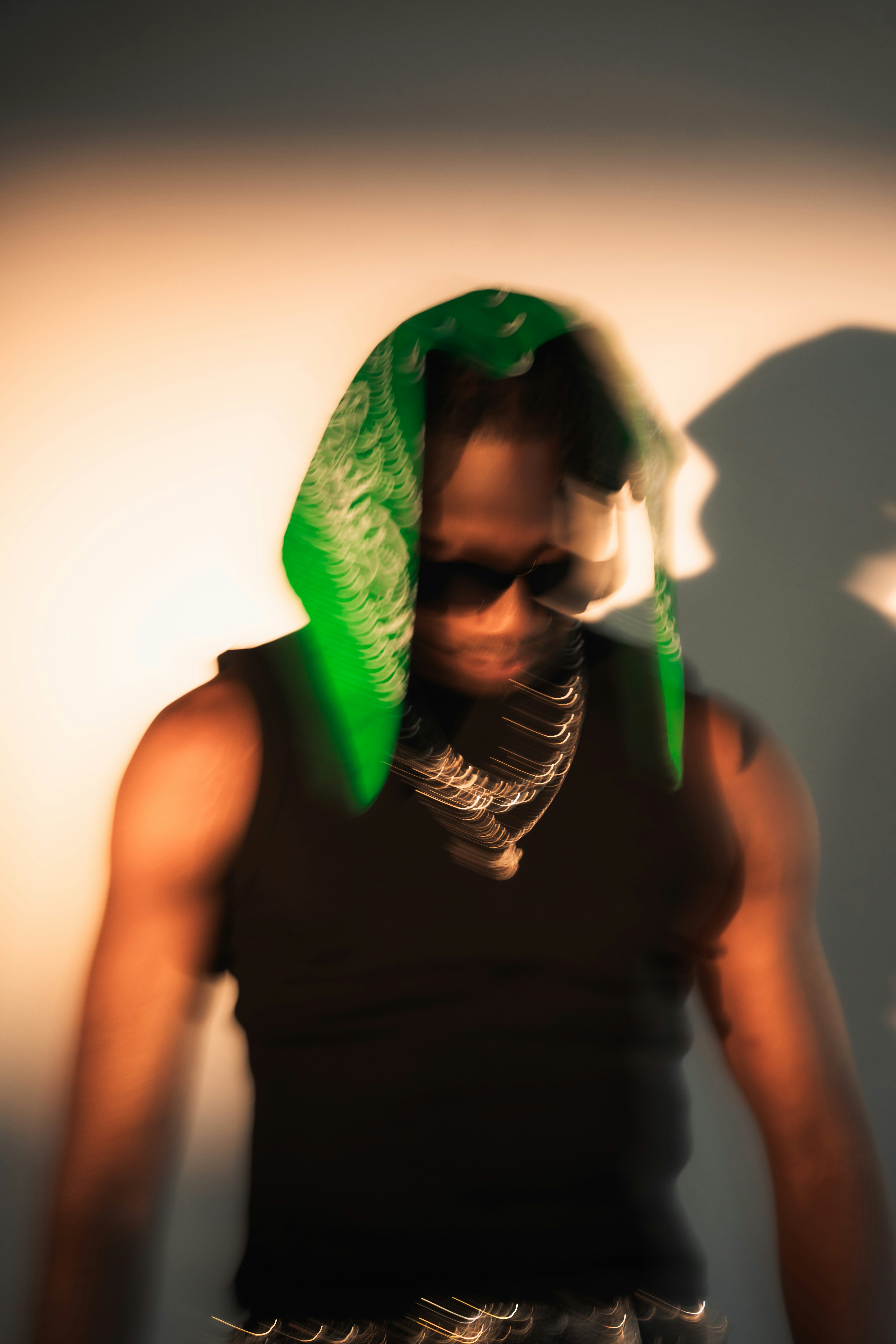 A person in a green bandana and black tank top with motion blur