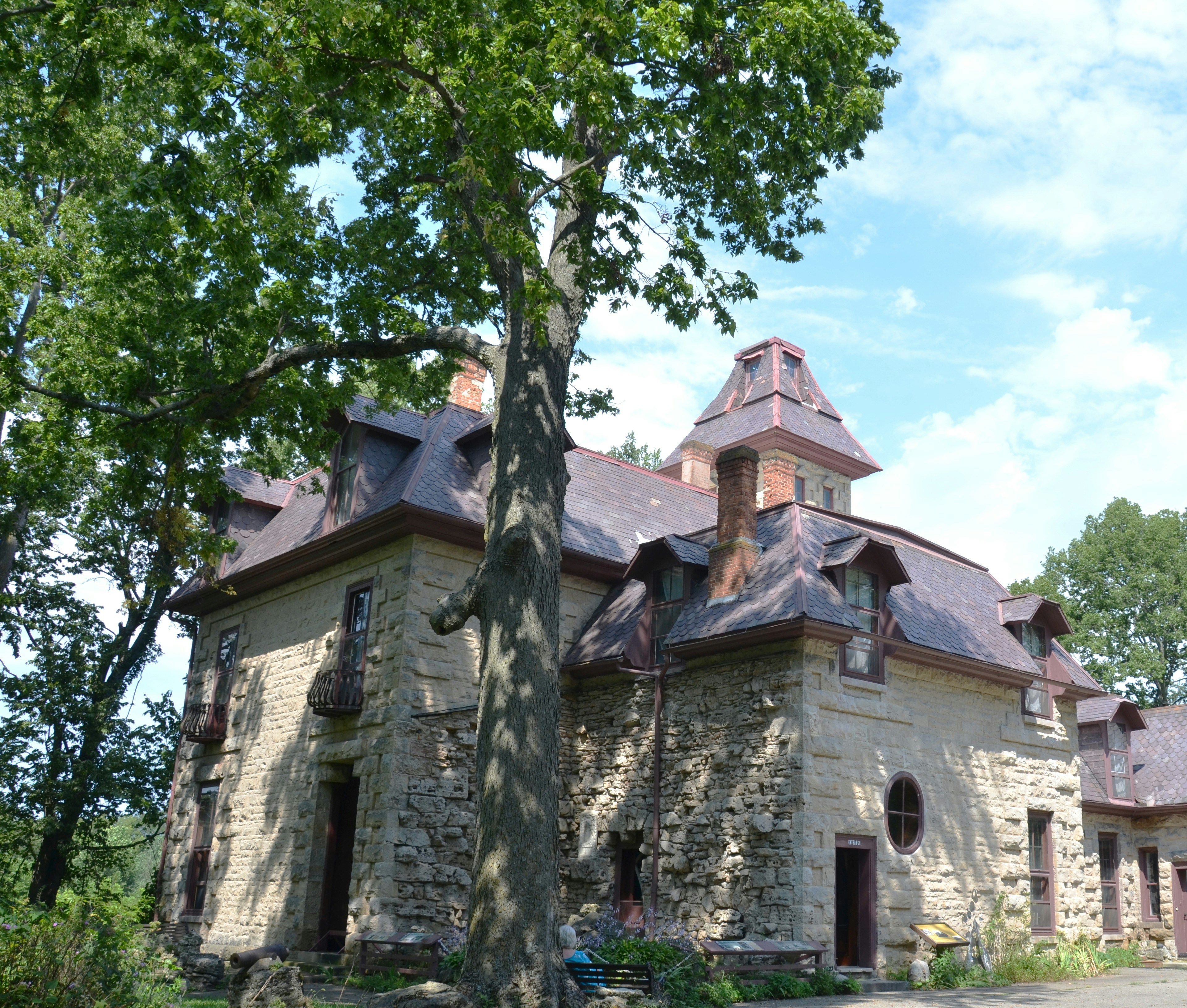 Old Stone Manor Amid Tall Shade: A Cottage Complex Framed by a Luminous Sky