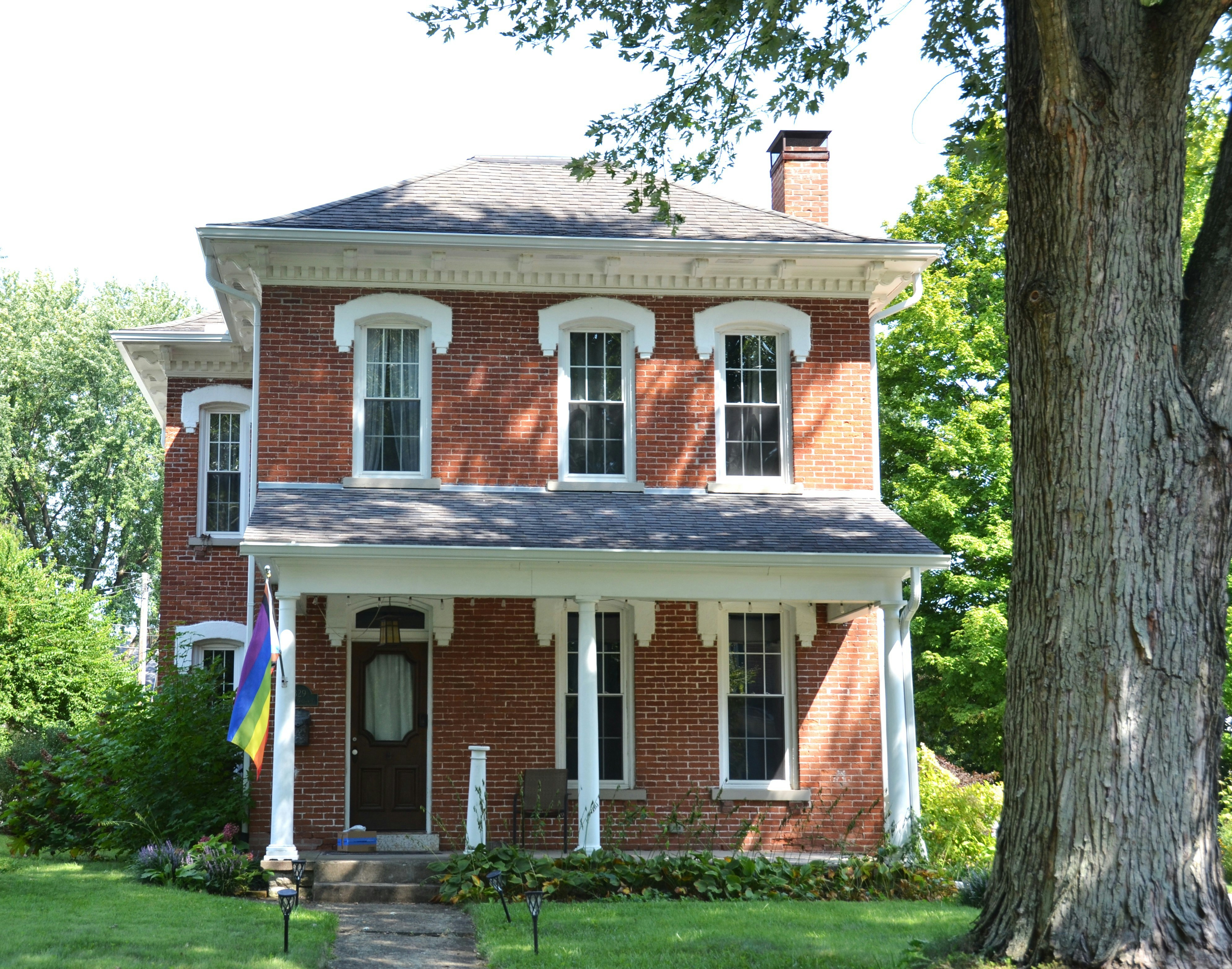 Brick Federal House with Front Porch in Sunlit Green Yard