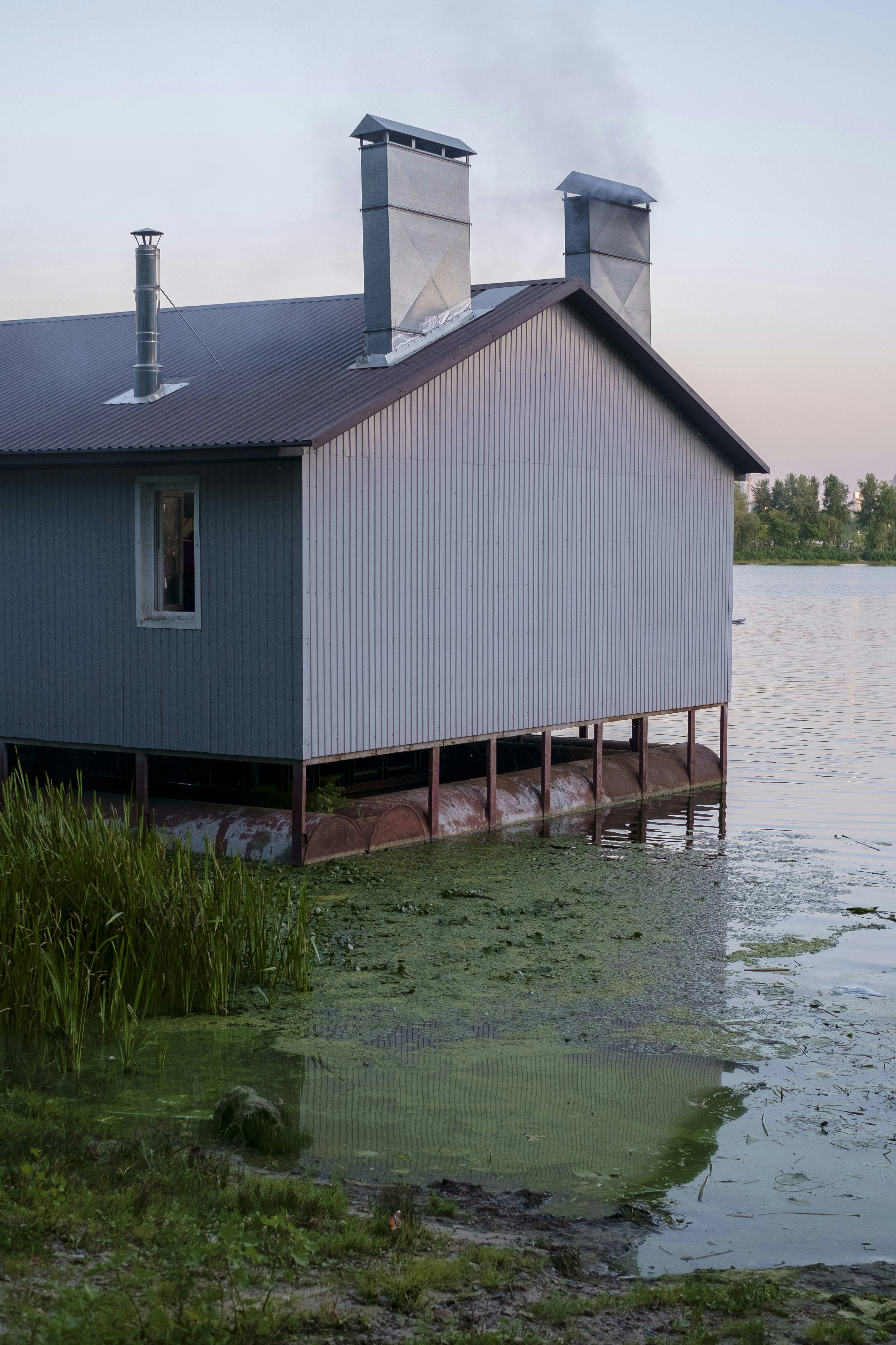 Blue Boathouse on stilts at quiet shoreline
