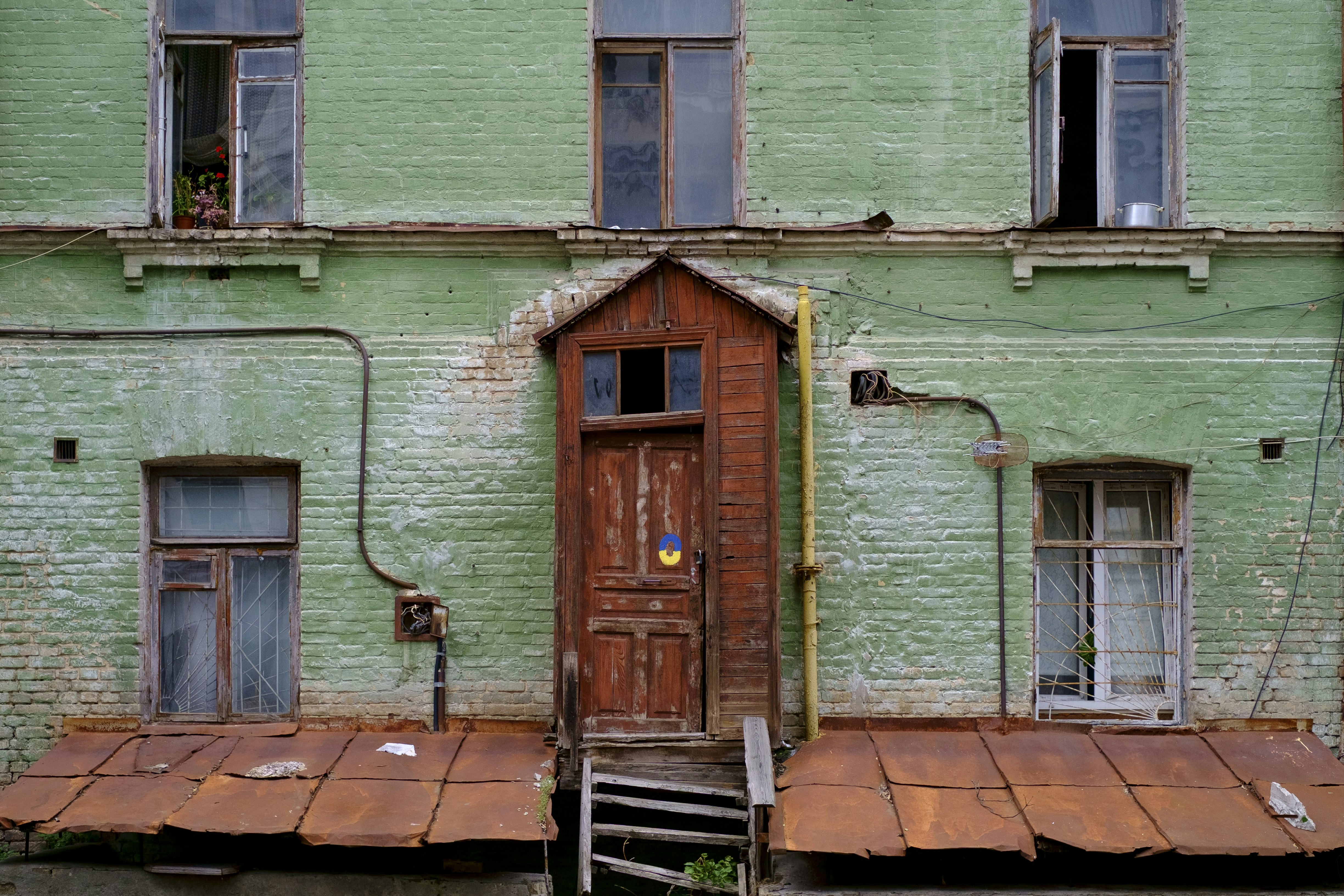 Weathered Green Facade: A Central Door Framed by Worn Windows
