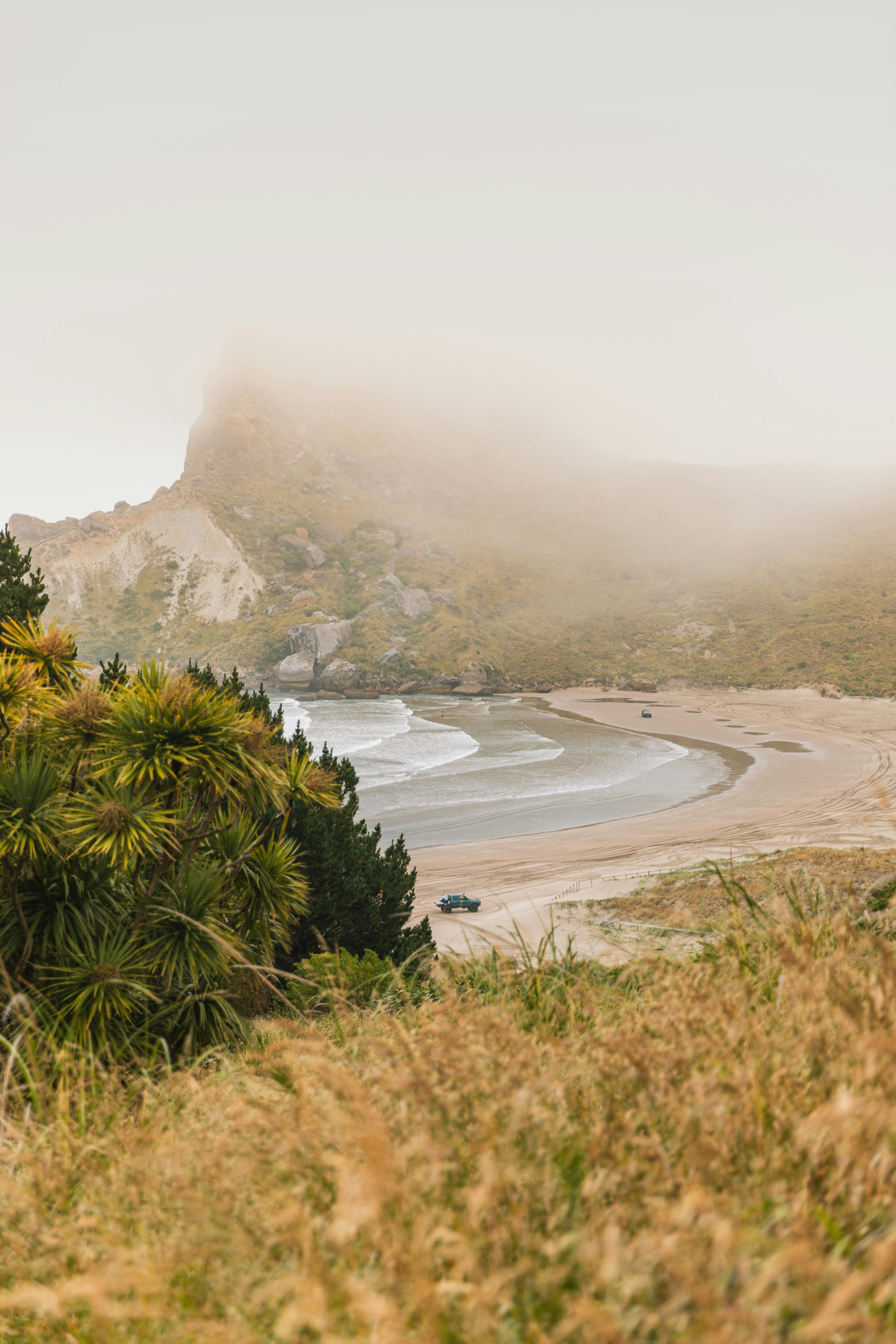 Mist over a Coastal Cliff: Quiet Beach Beneath a Fog-Shrouded Peak