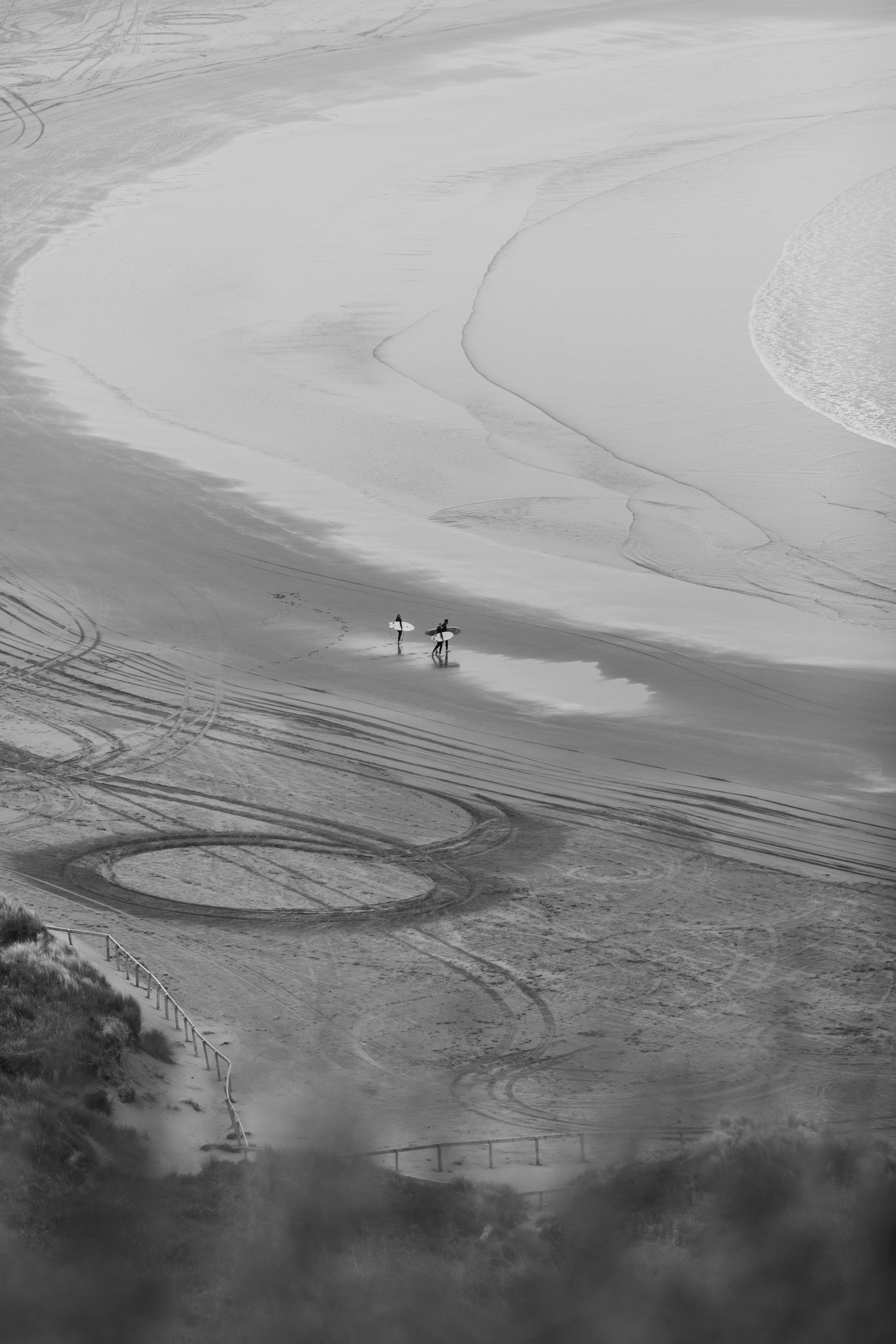 Tide-Traced Geometry: Surfers on a Quiet Shore