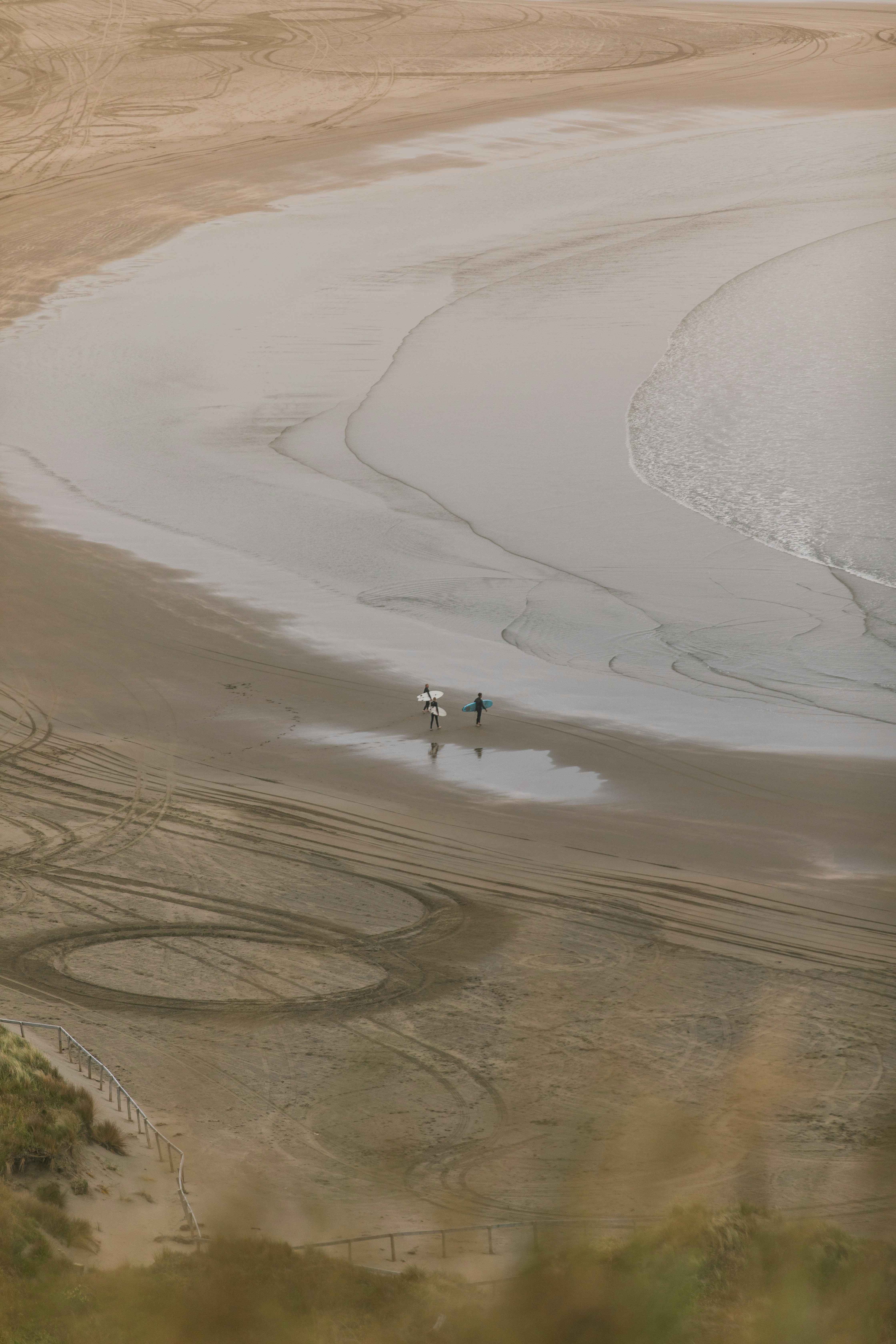 Drifters on the Wet Sand: Two Surfers Find Balance on a Quiet Shore