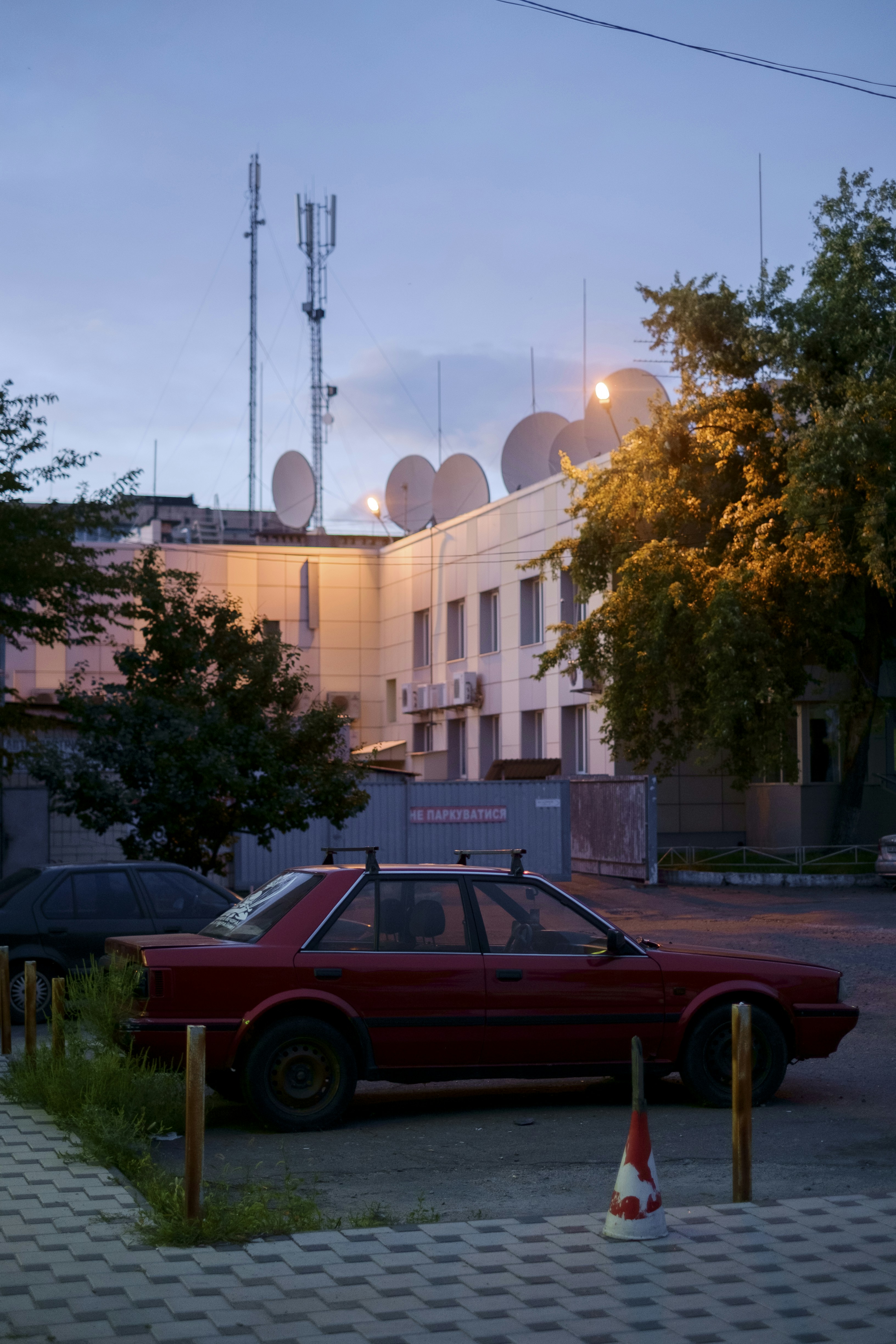 Red Sedan and Satellite Rooftop: Evening in the Industrial Yard