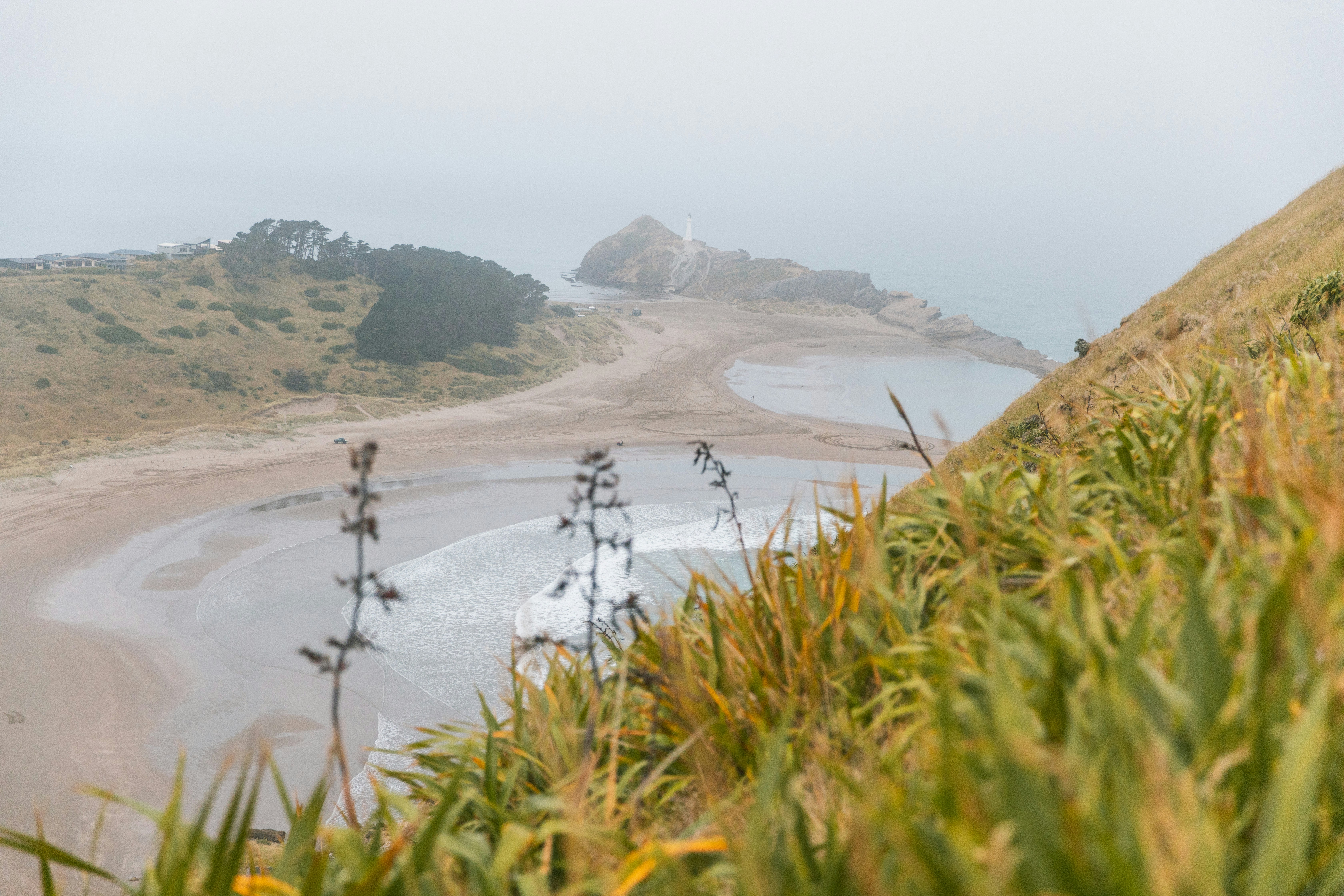 Coastal Curtain: Sloping dunes frame a misty shoreline
