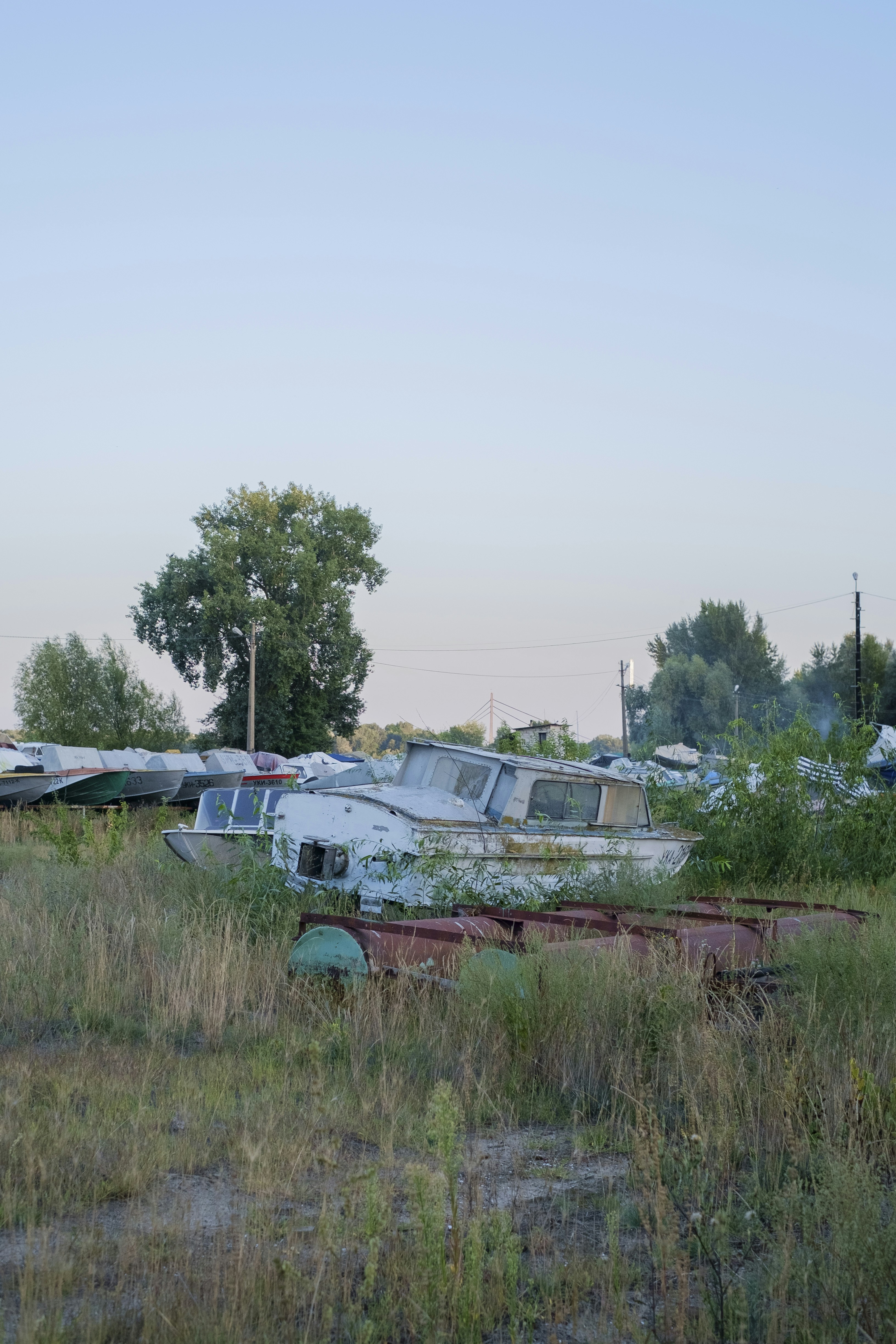 Sunlit Boatyard at Dusk: A Quiet Field of Forgotten Vessels