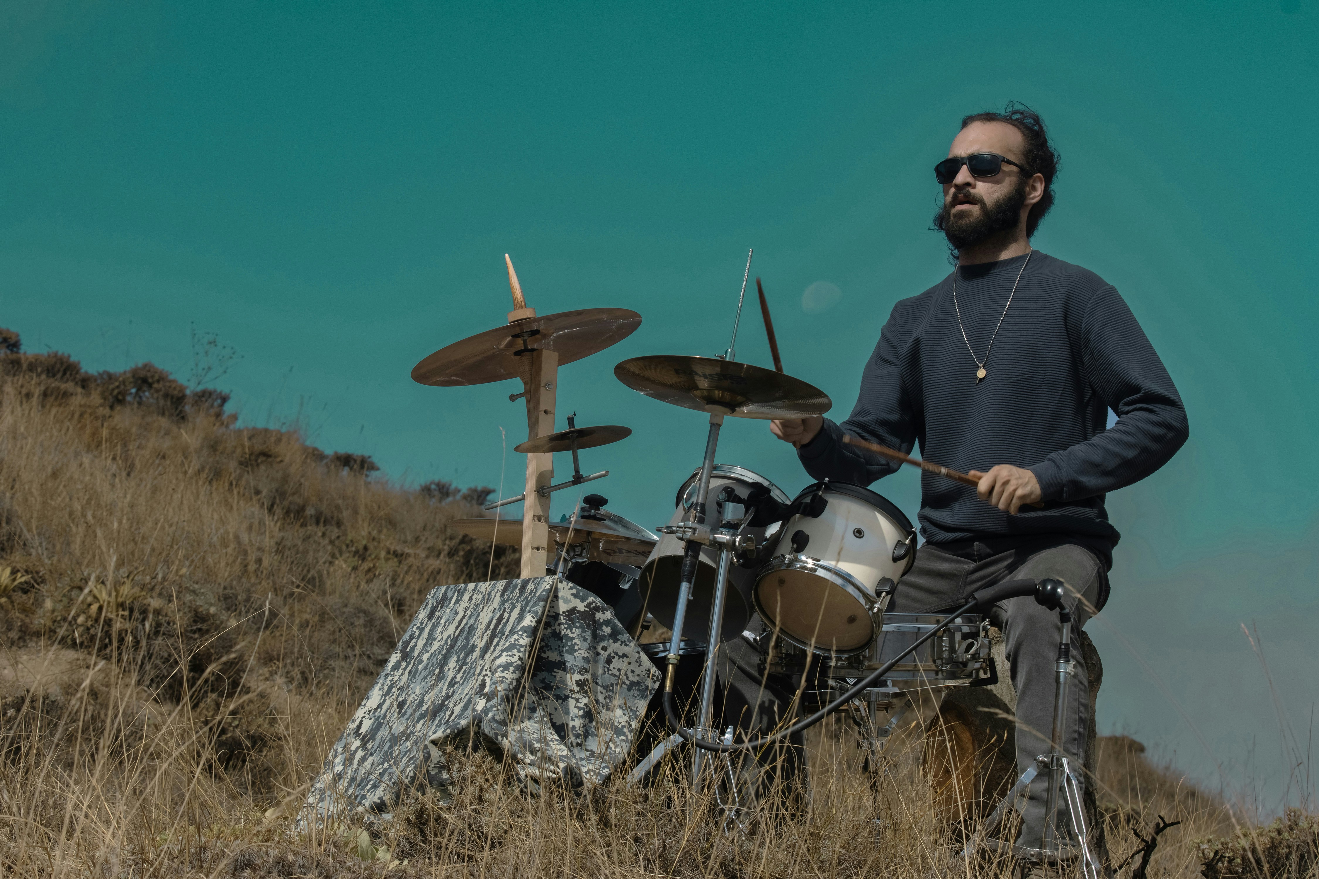 Drummer on the Crest: solo performance atop sunlit hillside