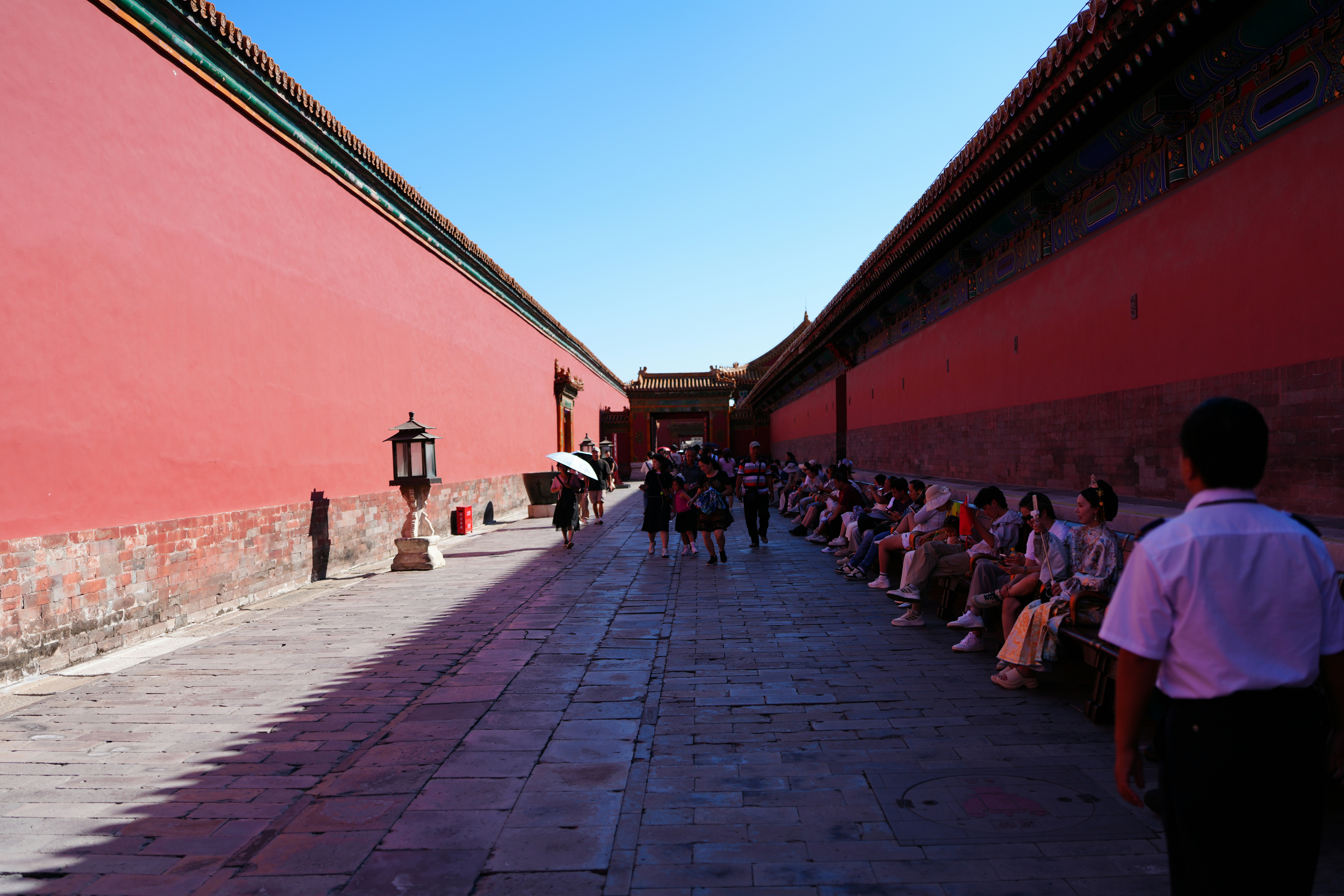 Long Red Wall Corridor: People Resting Along the Path