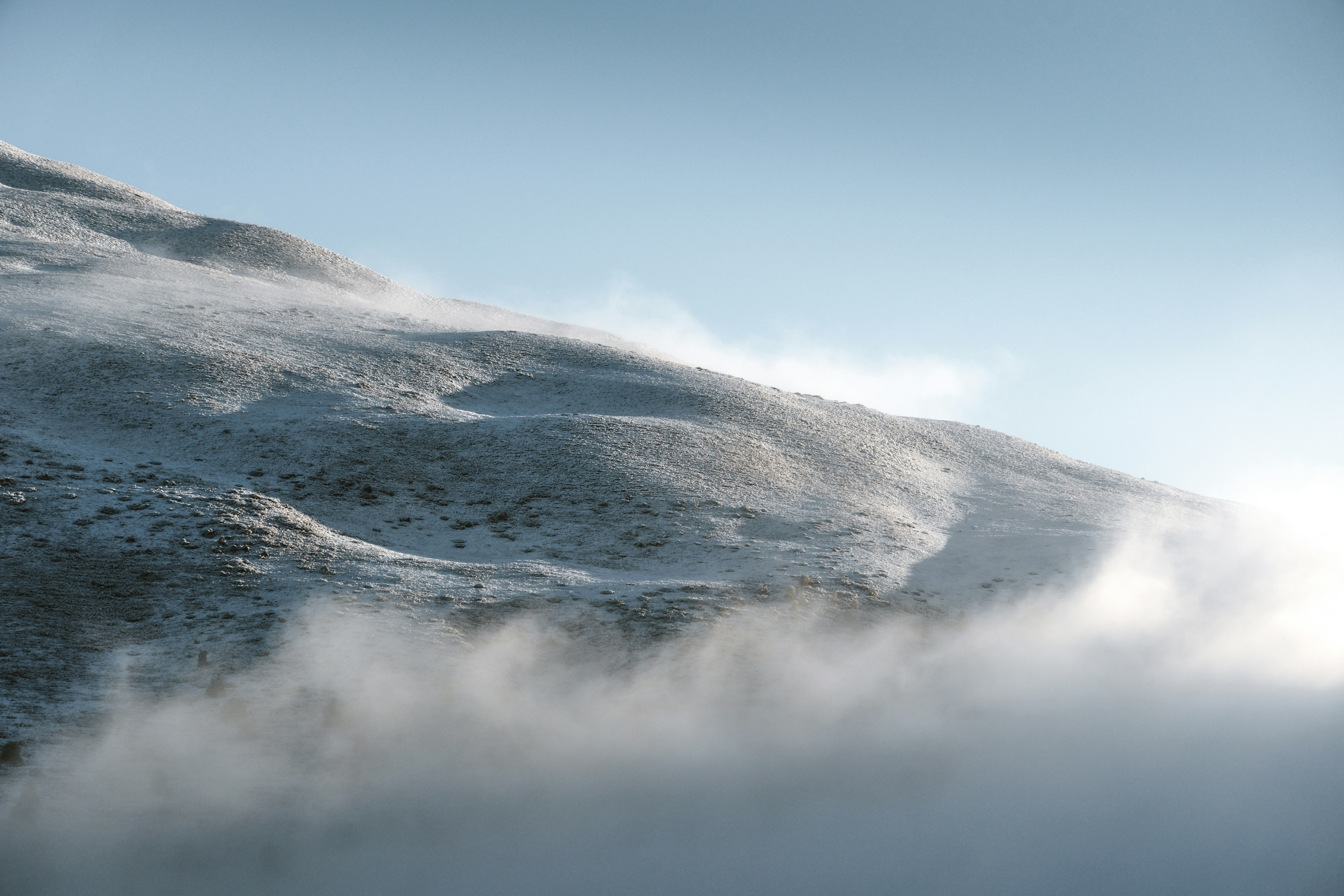 Quiet Summit: A Snow-Dusted Ridge Emerging from Clouds