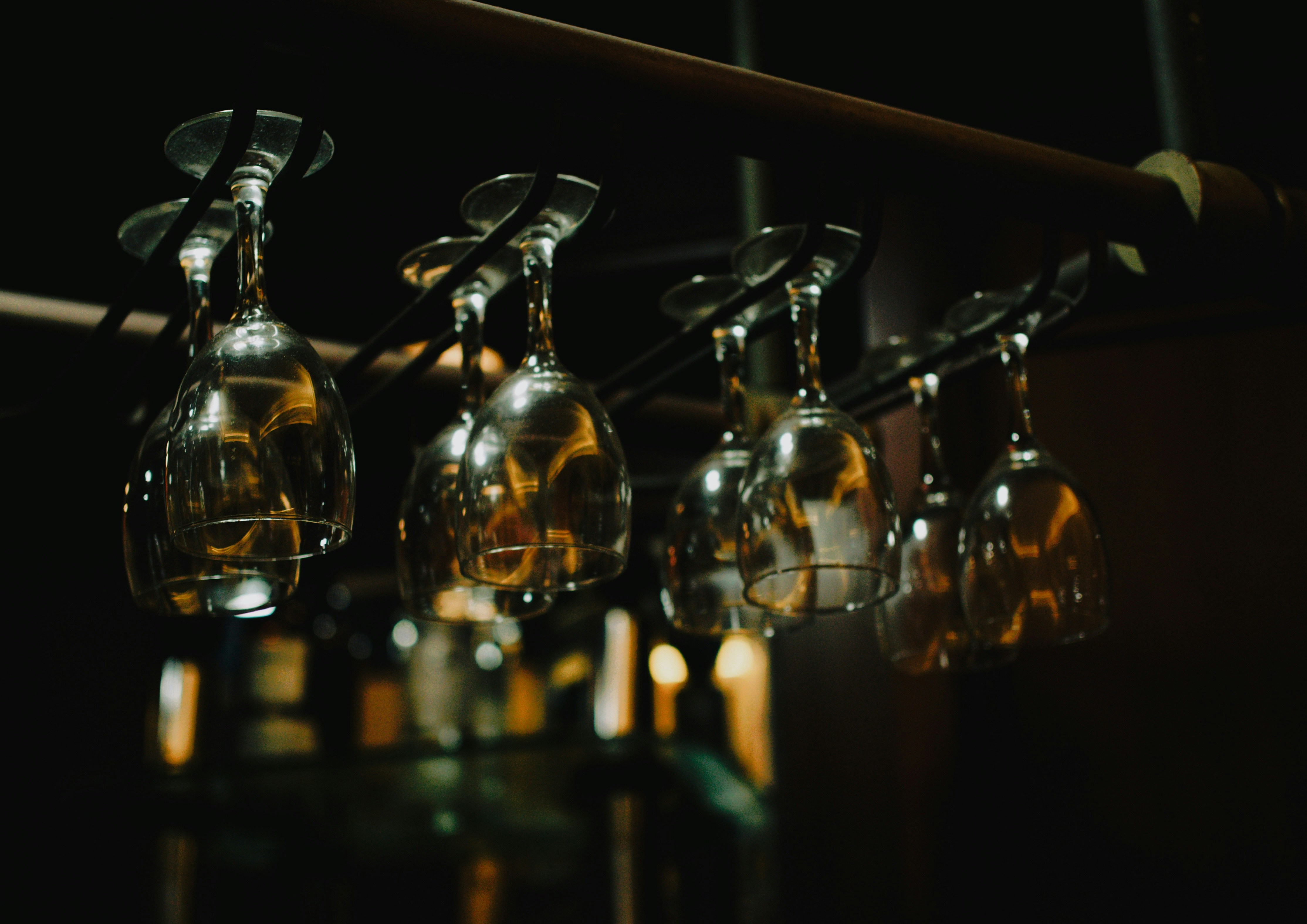 Coppery Glasses: Distant Bar Lights Through Hanging Stemware