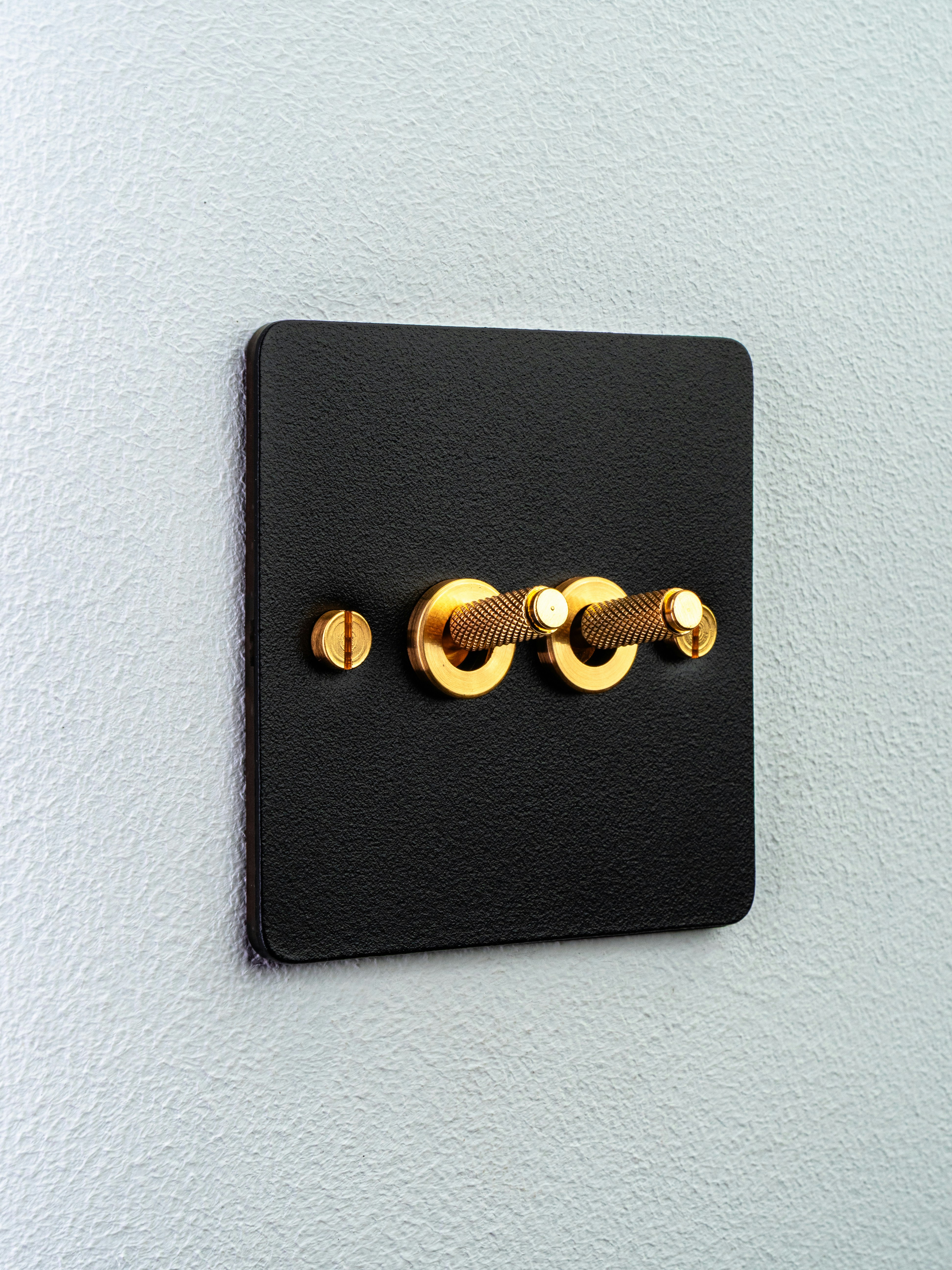 Gold Knurls on a Black Plate: Close-Up of a Wall-Mounted Fixture