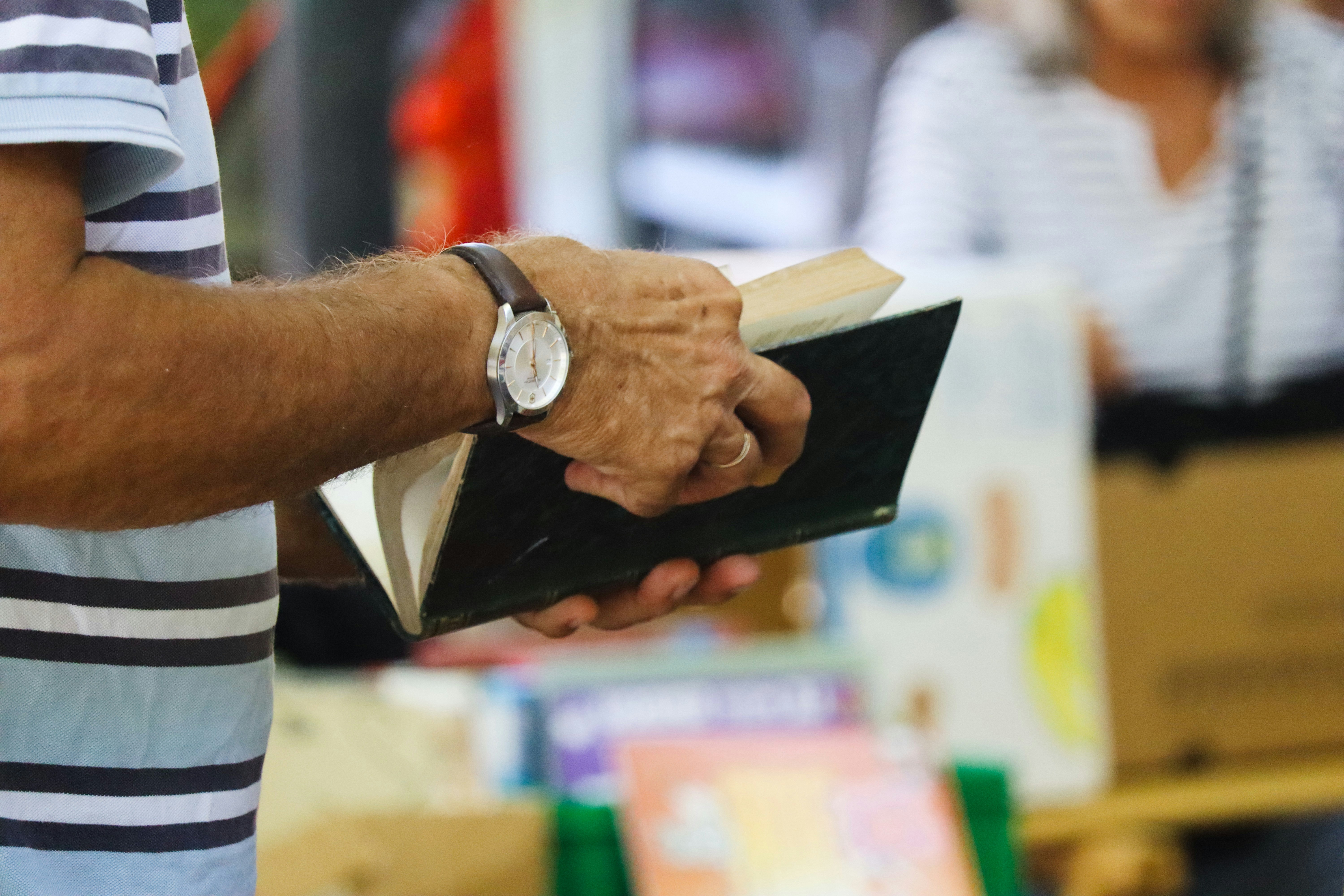 Hands, Notebook, and Watch: A Studious Moment in a Busy Market
