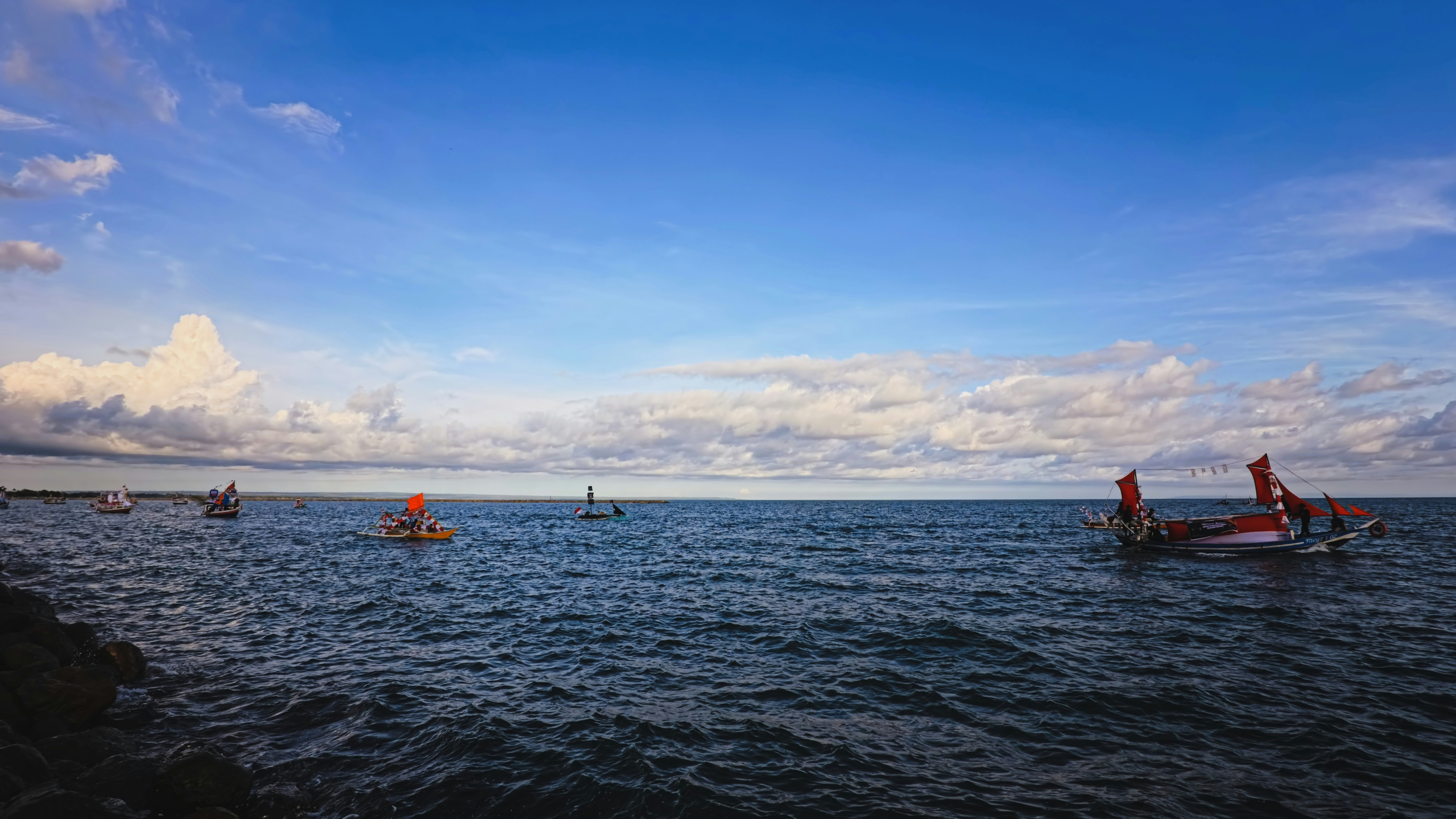 Red-sailed Outriggers on a Calm Sea