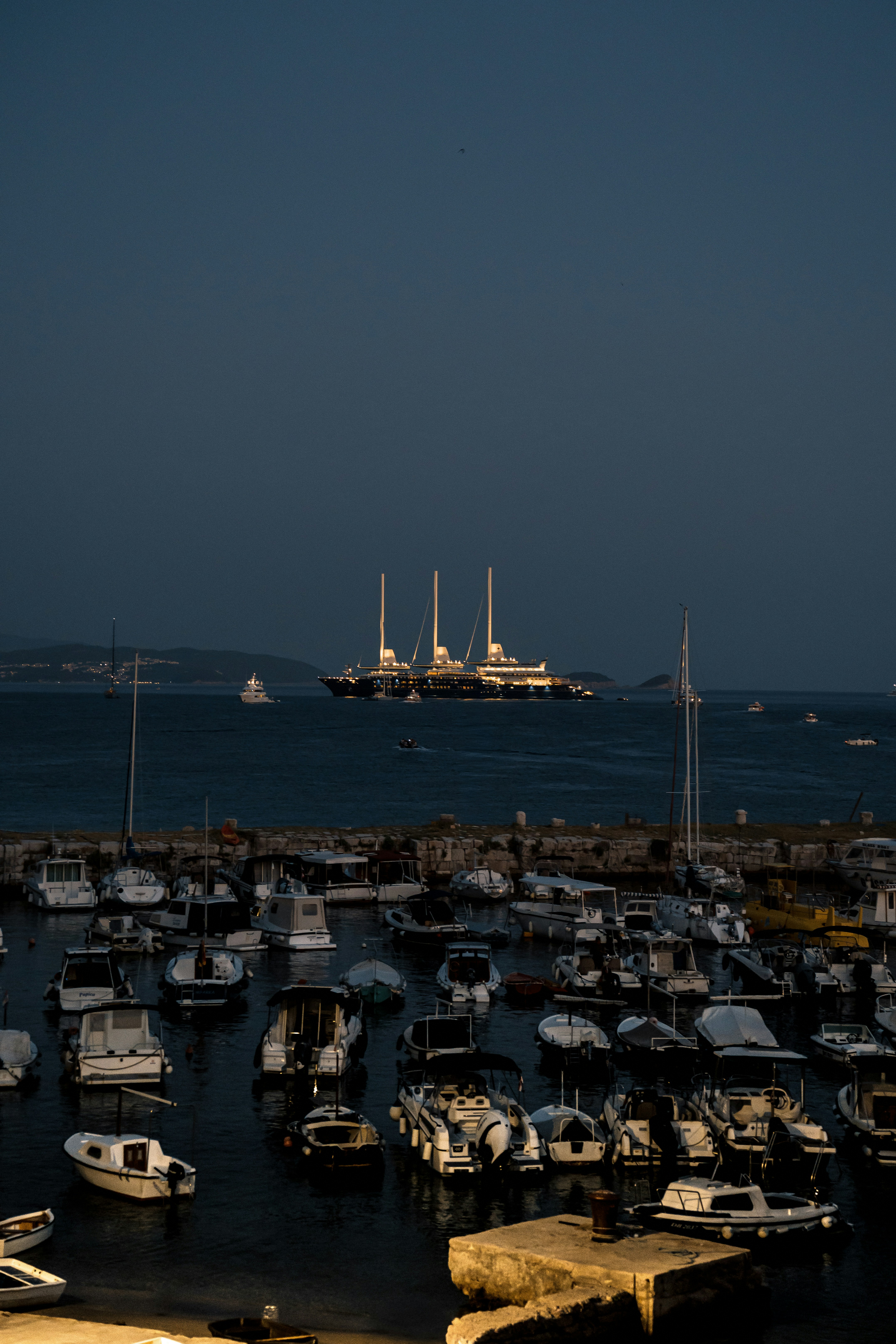 Sailing into Blue Hour: A Fleet at Dusk Overshadowed by a Grand Yacht