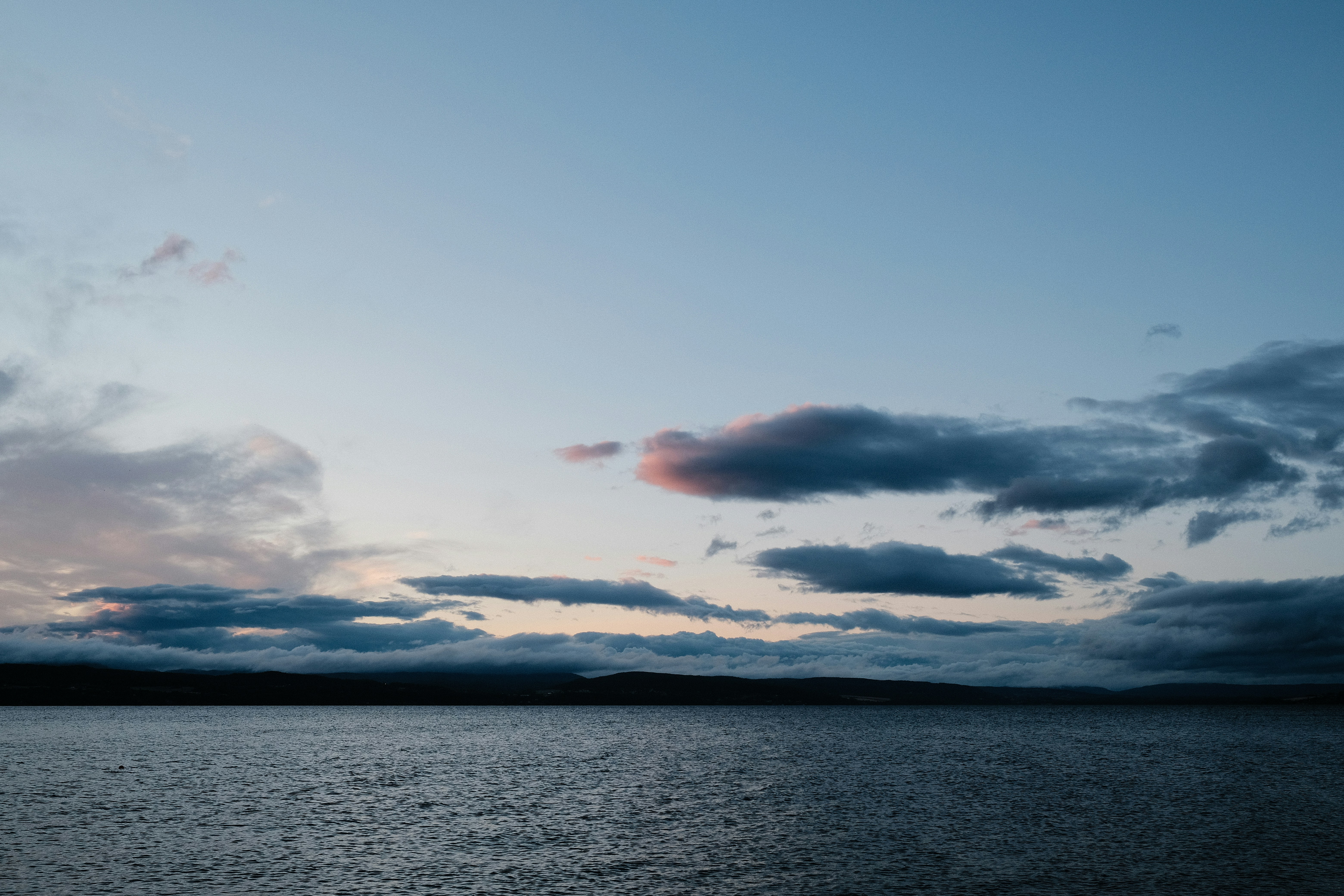 Dusk over a Calm Fjord: Clouds Hover Above the Quiet Horizon