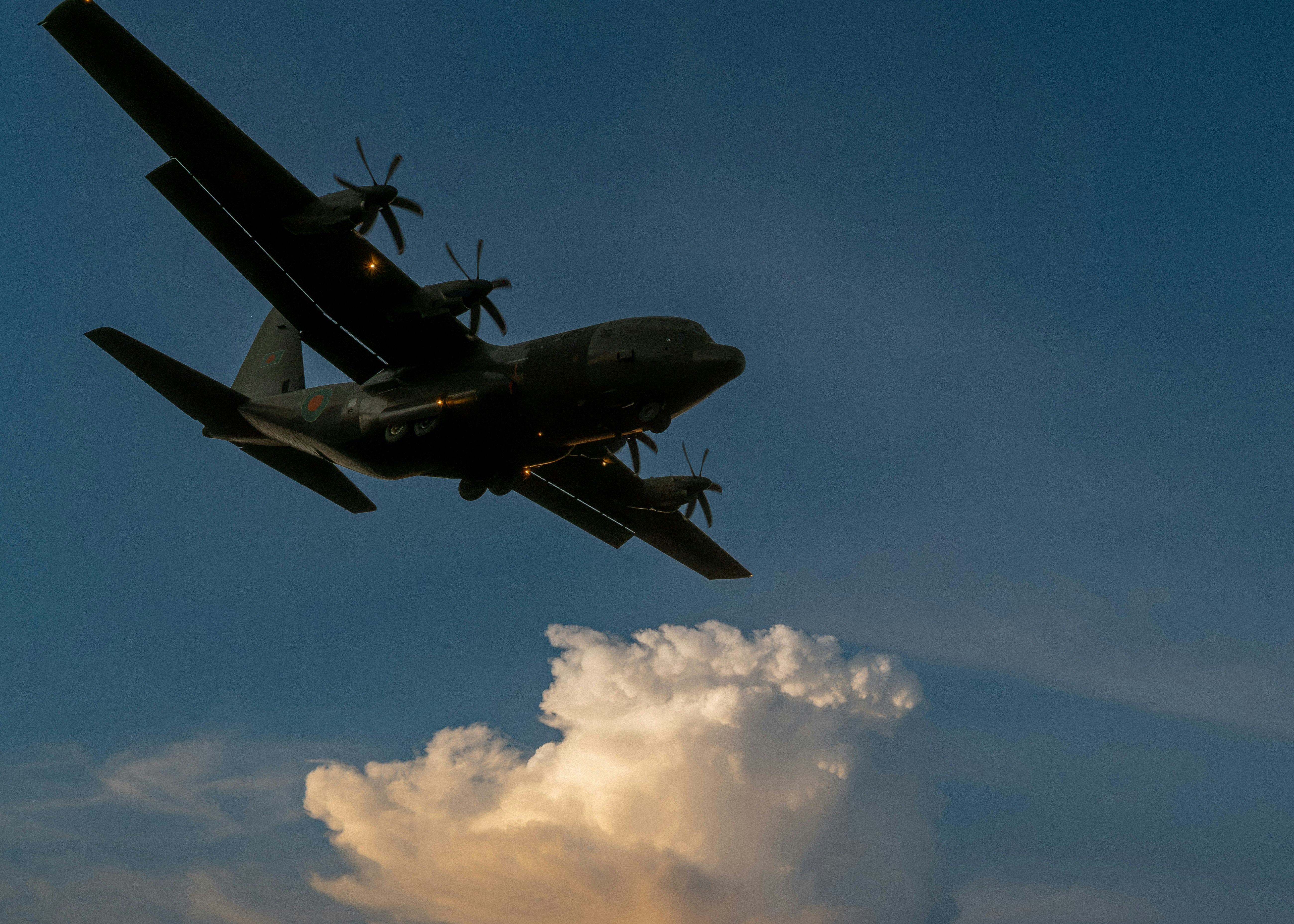 Skyward Lift: A Military C-130 Cutting Through a Copper-tinged Cloudscape
