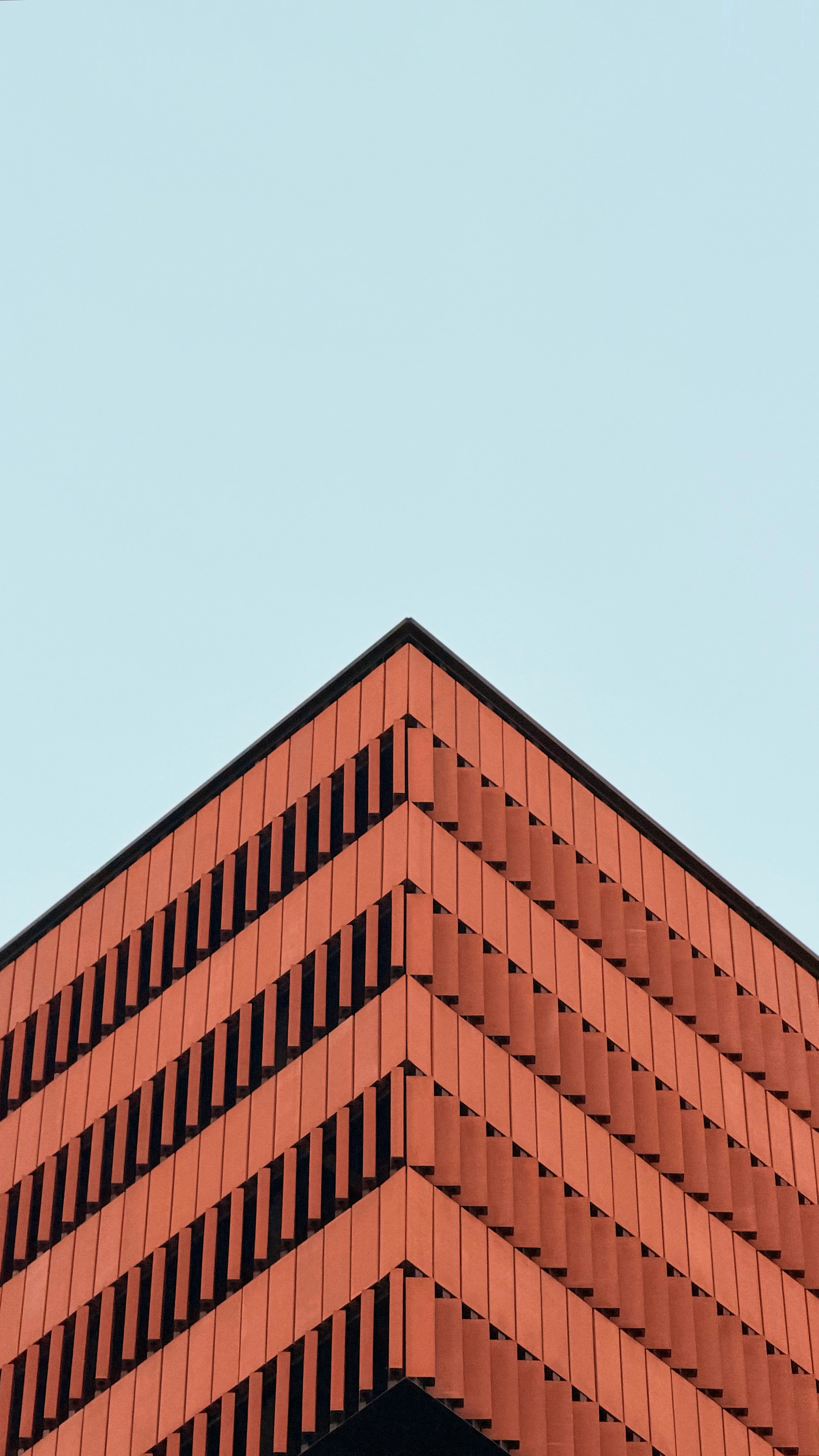 Constructed from an arrangement of vermilion bricks, the building reveals a unique sense of rhythm, a quality of breathability, and symmetrical beauty when viewed from specific angles.