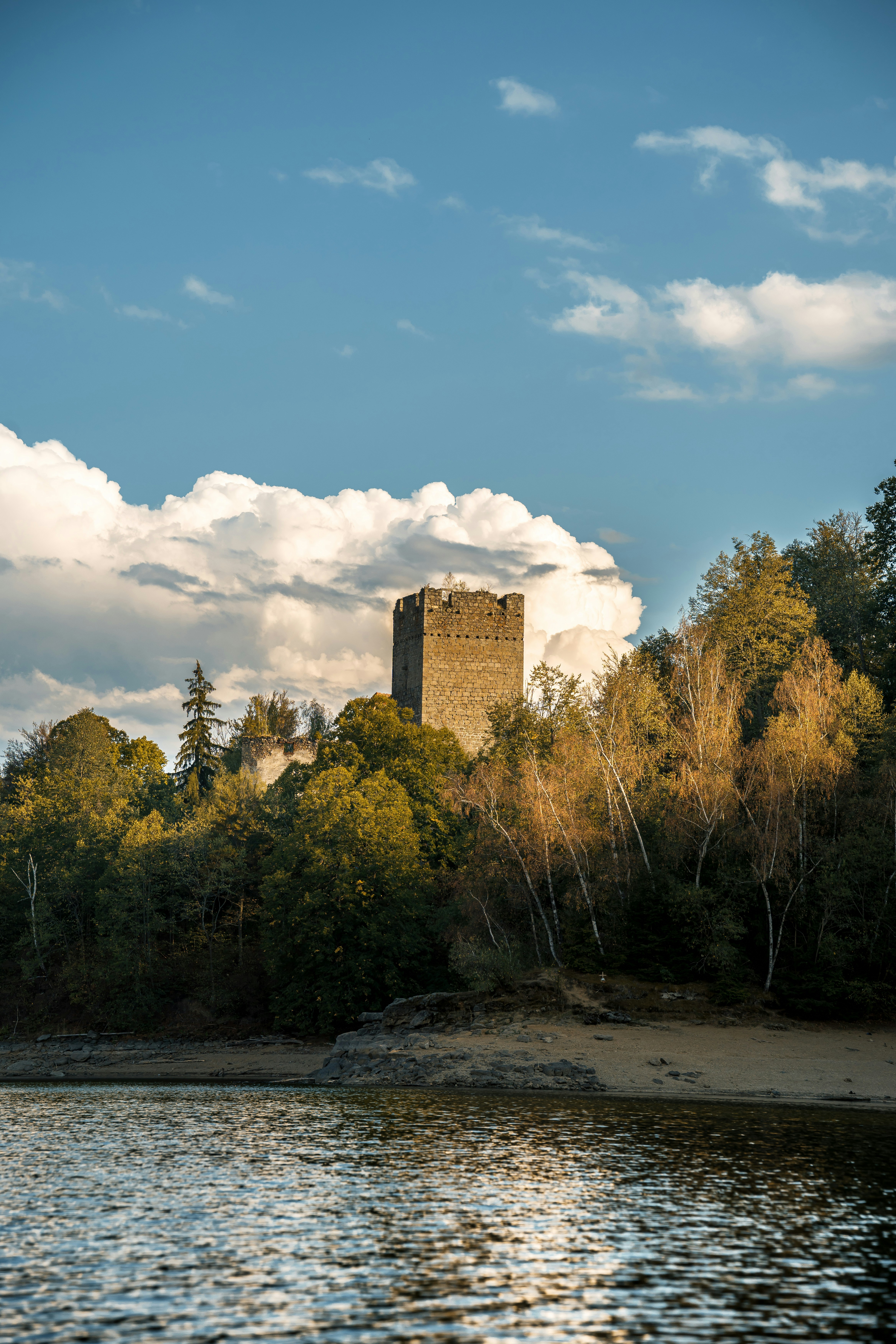 Castle on the Hill: A Riverside Watchtower Surrounded by Autumn Trees