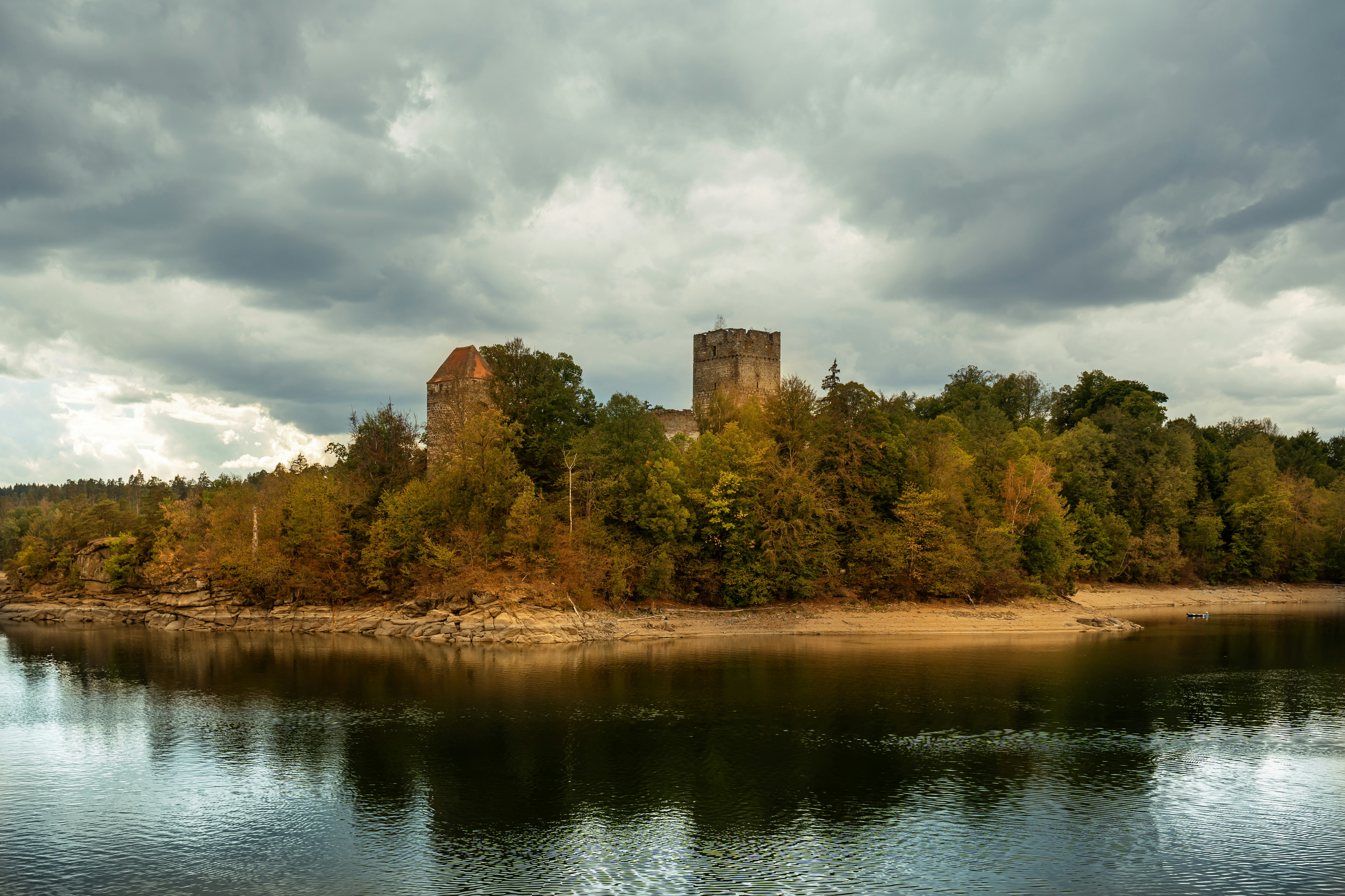 Castle Remnant Quietly Fringed by Autumn Trees Across a Calm River
