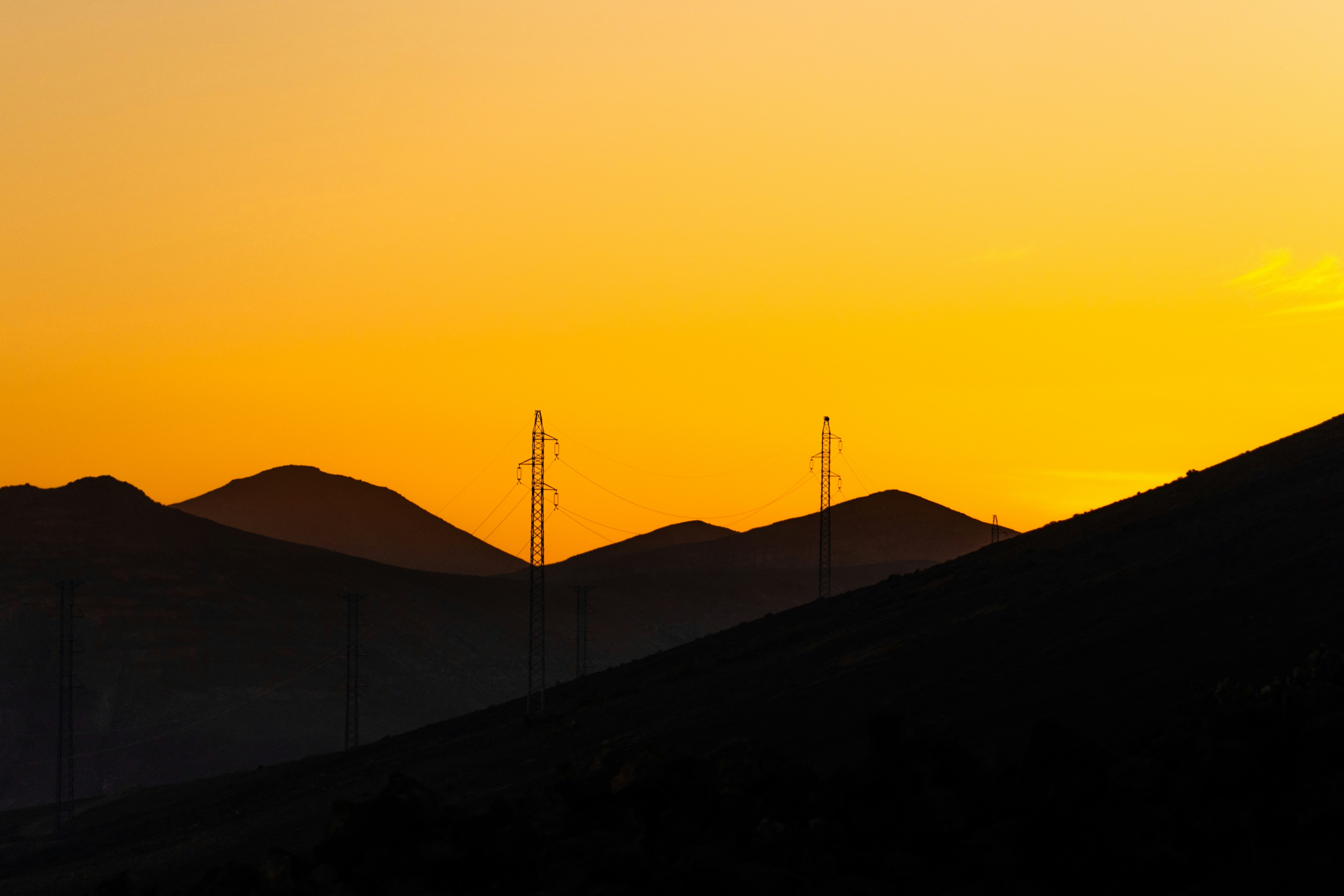Silhouetted hills at golden hour with power lines tracing the horizon