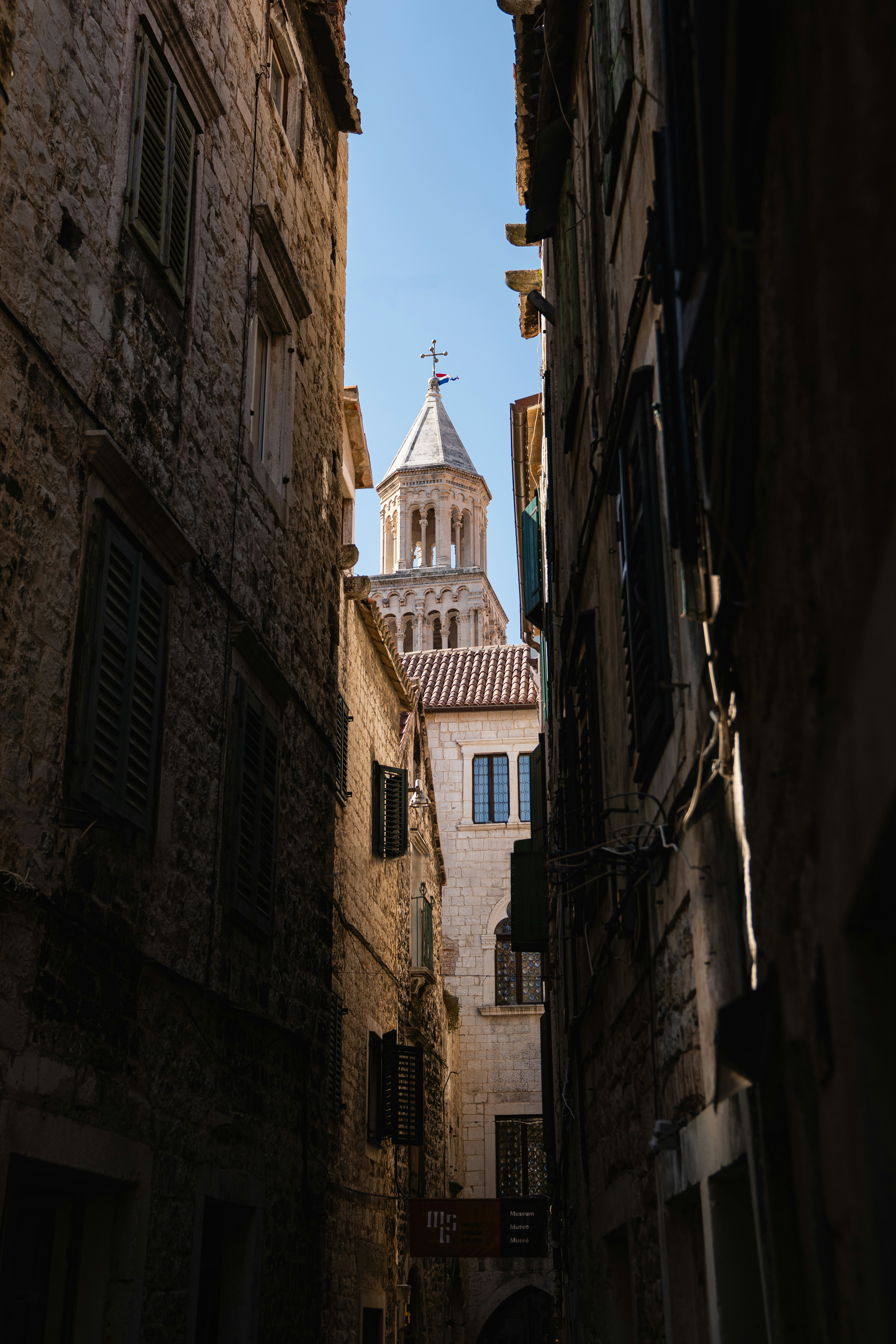 Light Between Stone Walls: A Narrow European Alley Reaching Toward a Bell Tower