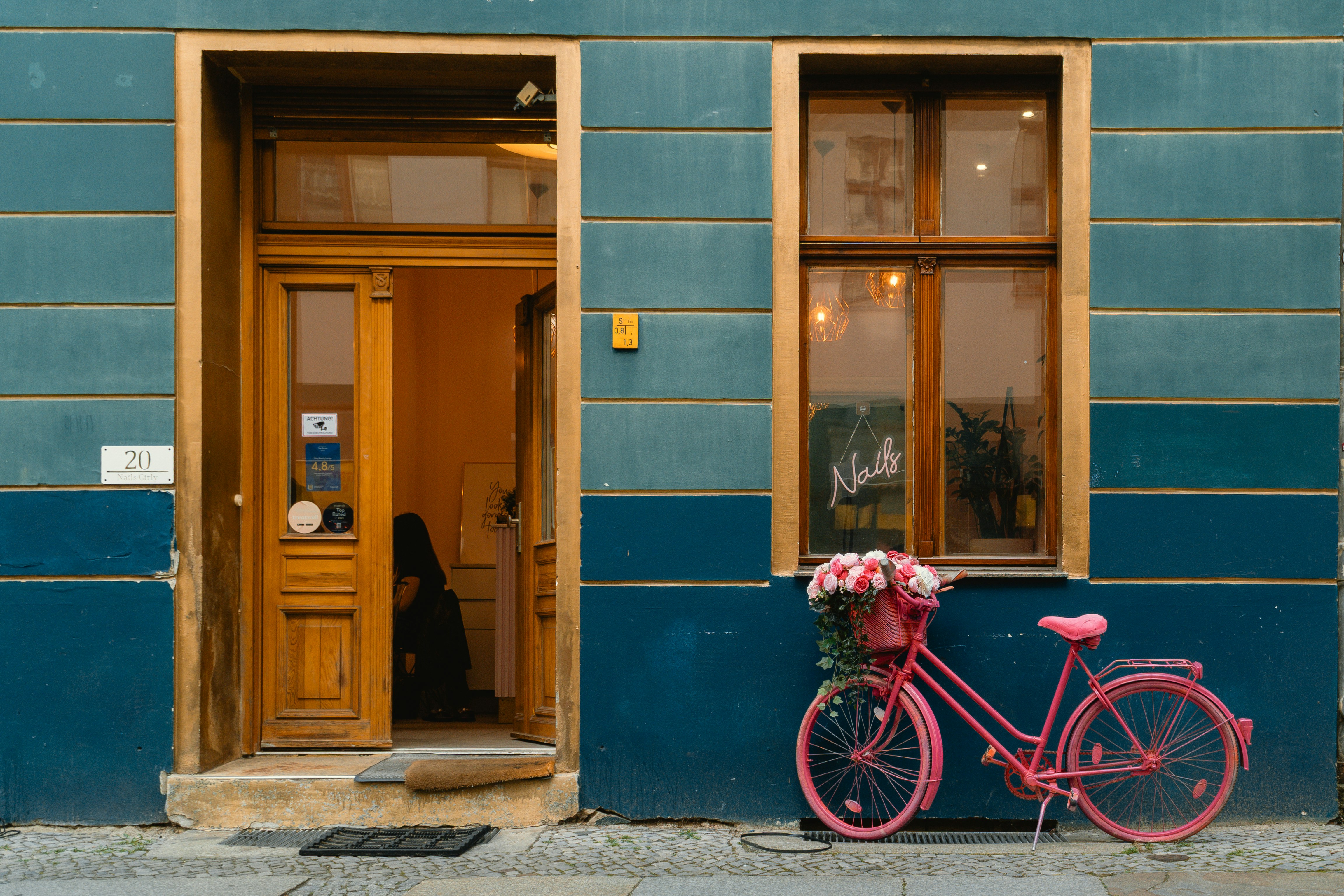 Pink Bicycle by a Turquoise Streetfront and Sunny Doorway
