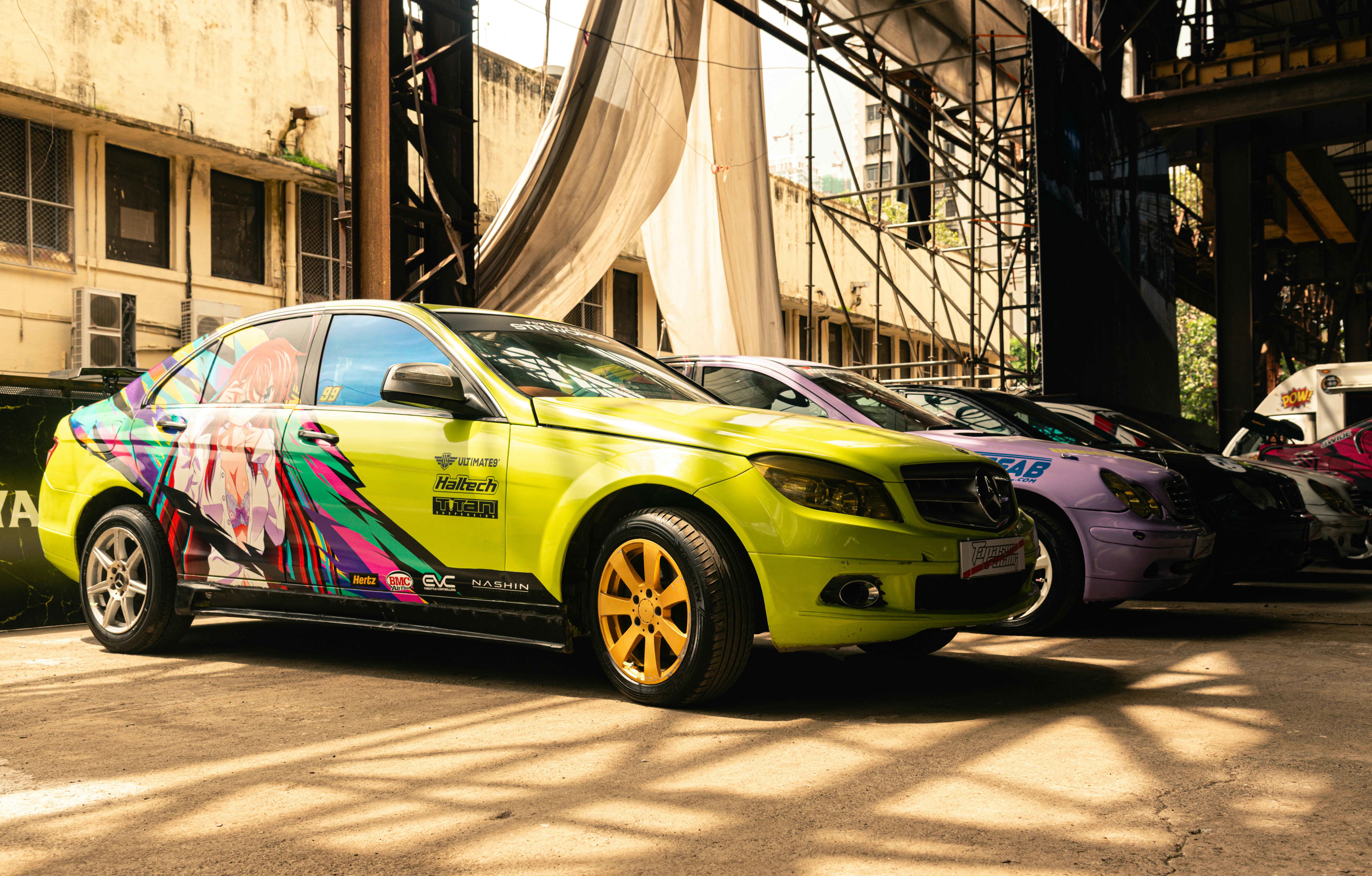 Sugar-coated sprint: a lime-green taxi with graphic wrap parked under industrial rigging