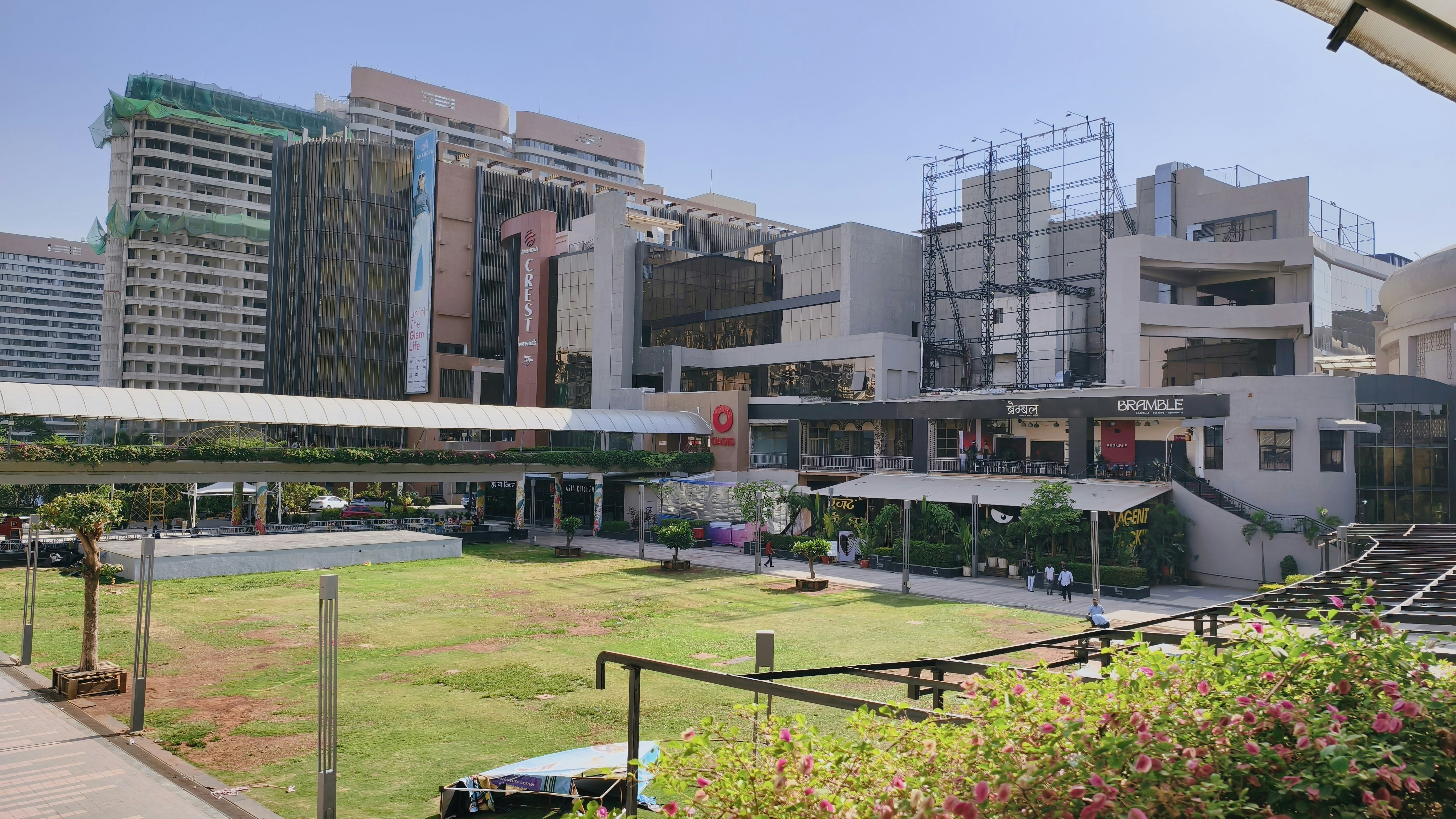 Wide-angle view of a modern university courtyard with green lawn, pathways, and contemporary buildings in the background.