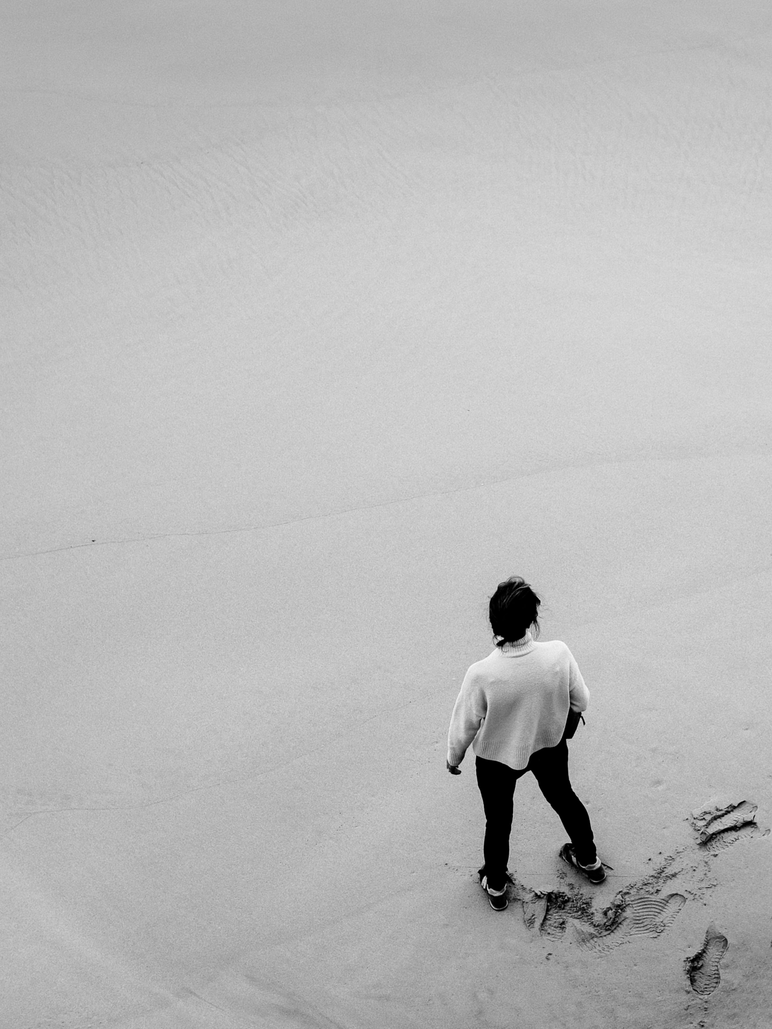 Solitary Walk on Quiet Sand: A Pale Shore in Monochrome