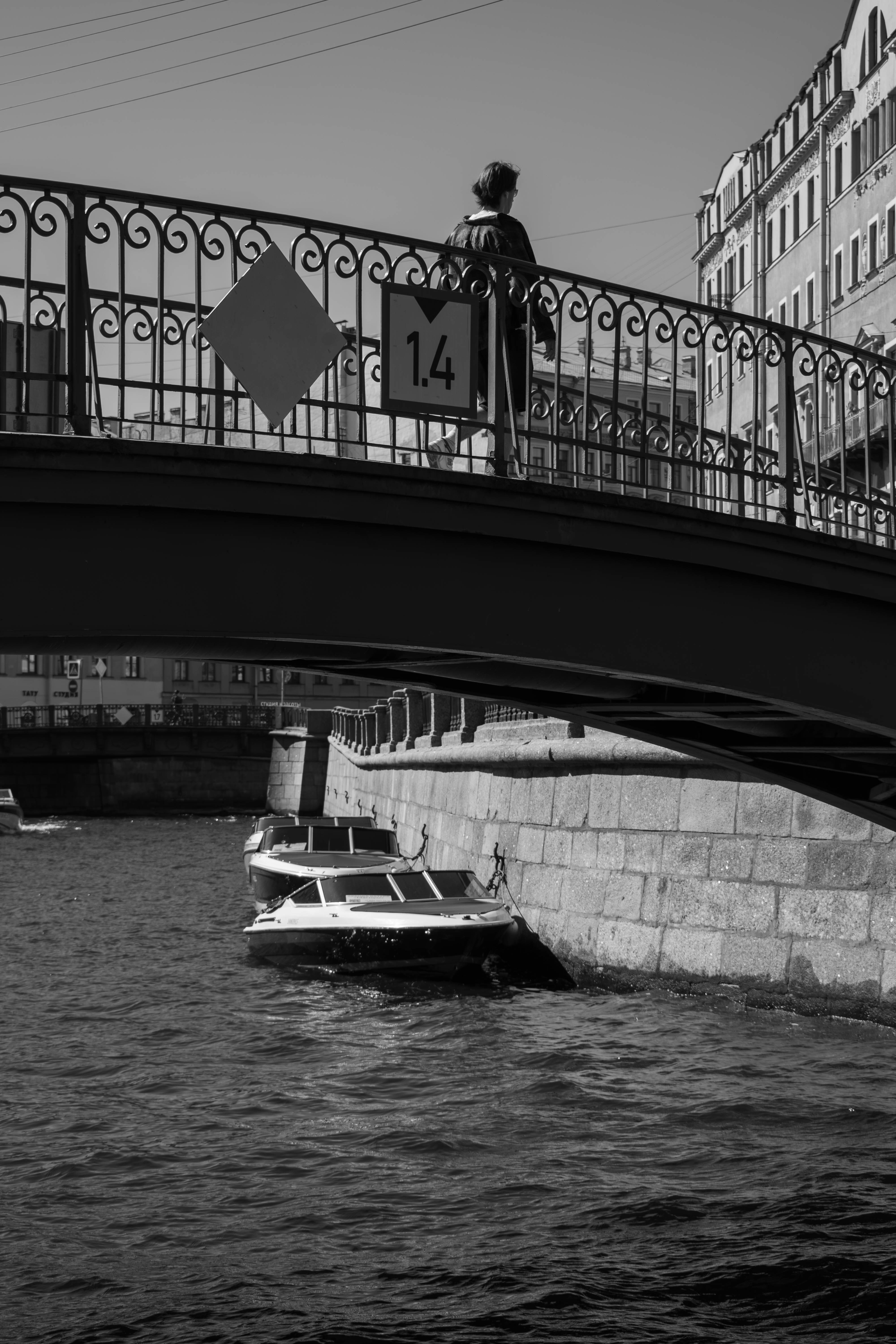 Concrete river crossing: lone figure on a wrought-iron bridge