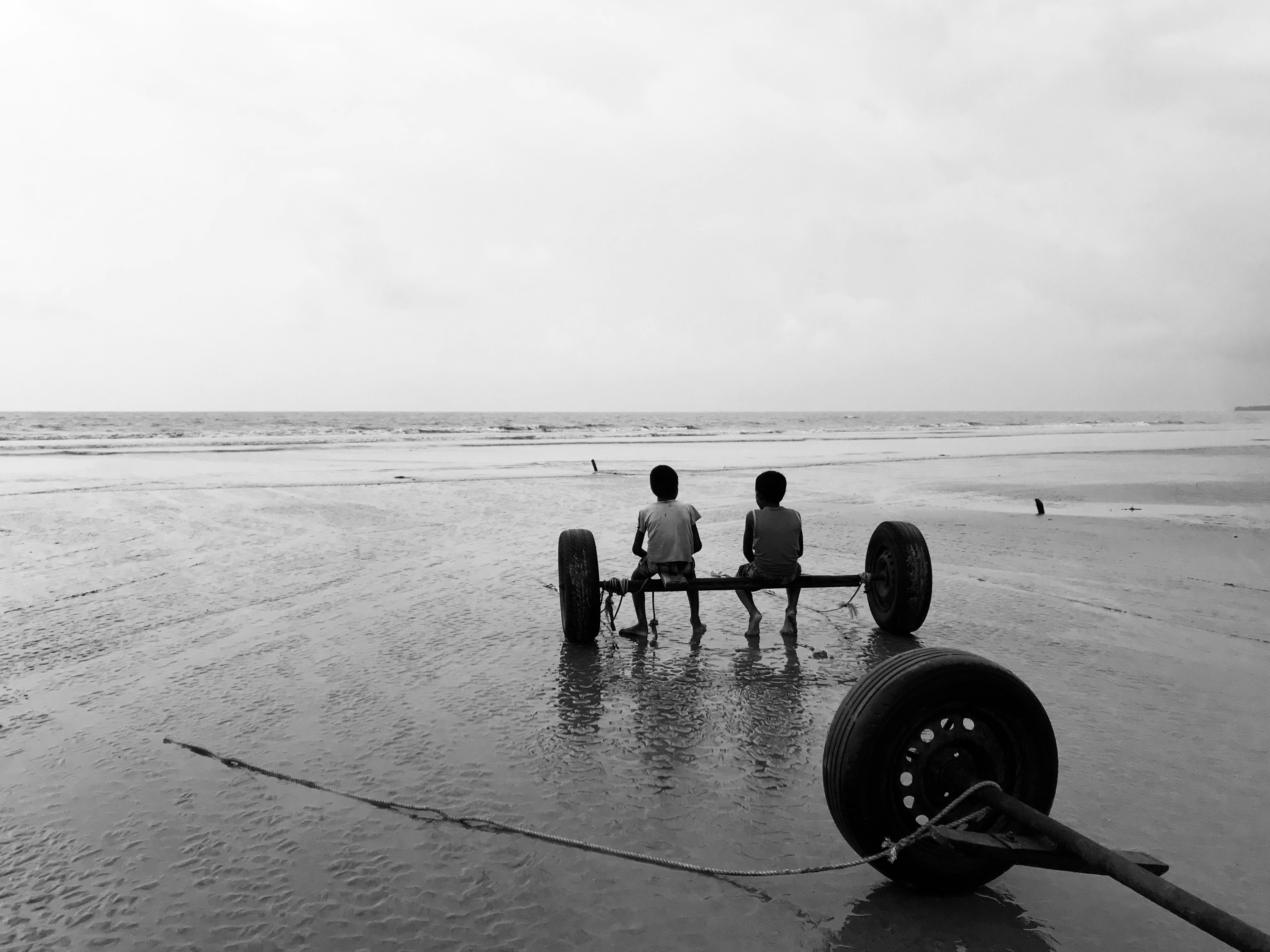 Two silhouettes on a drifting cart in a quiet shoreline horizon