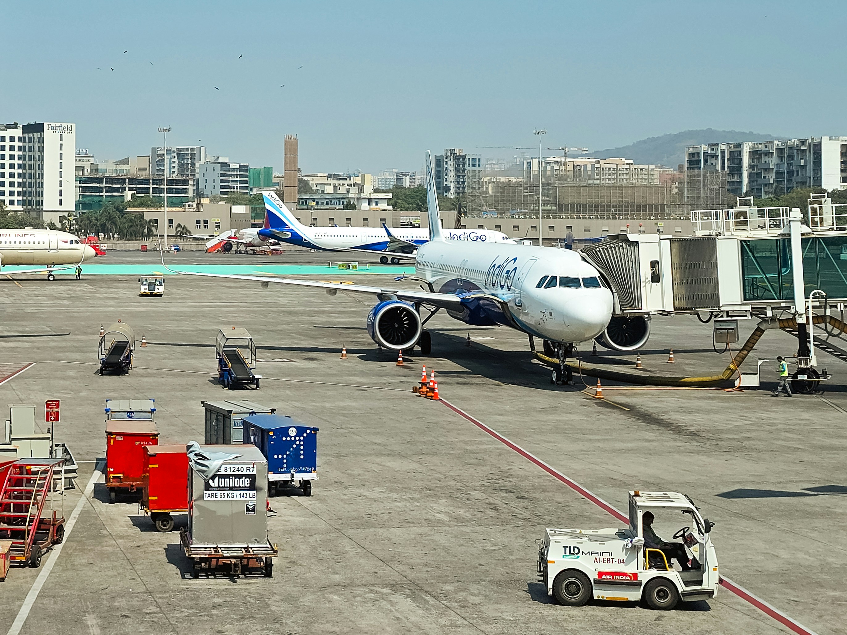 Jet at Gate: A Quiet Ramp Moment with Ground Support and Cityscape