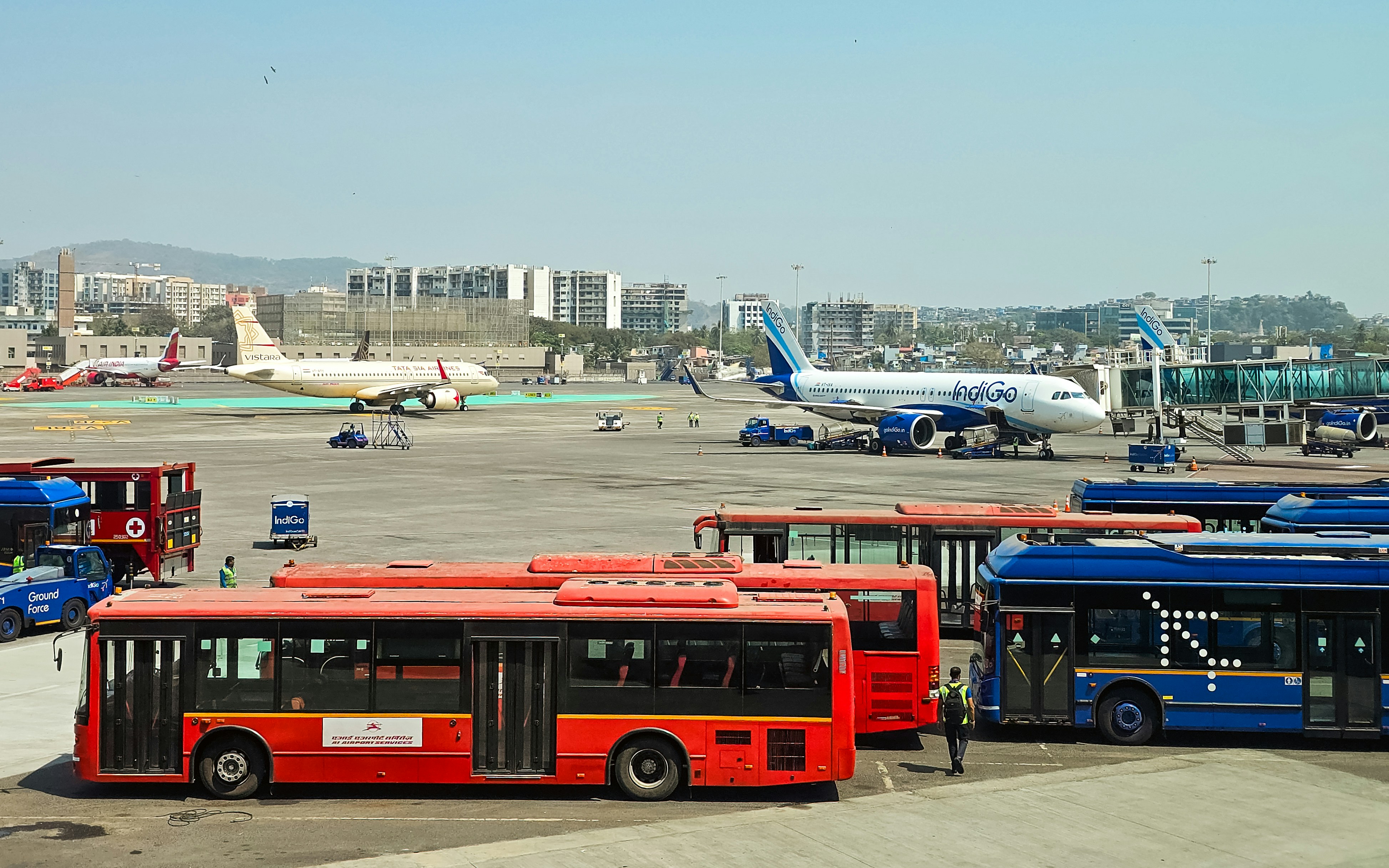 Grounded in Transit: Red Buses at a Busy Airport Apron