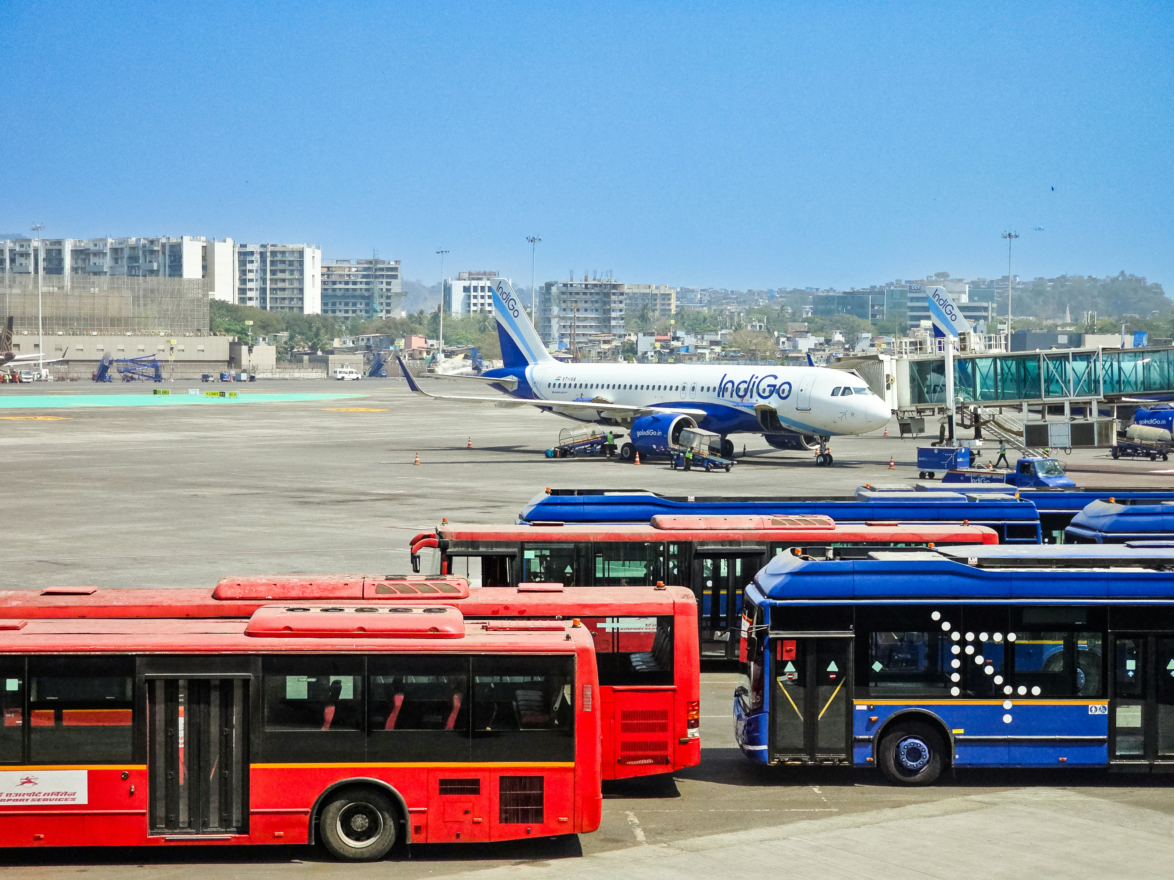 Grounded in Transit: Buses and a distant Indigo Jet at a Busy Airport
