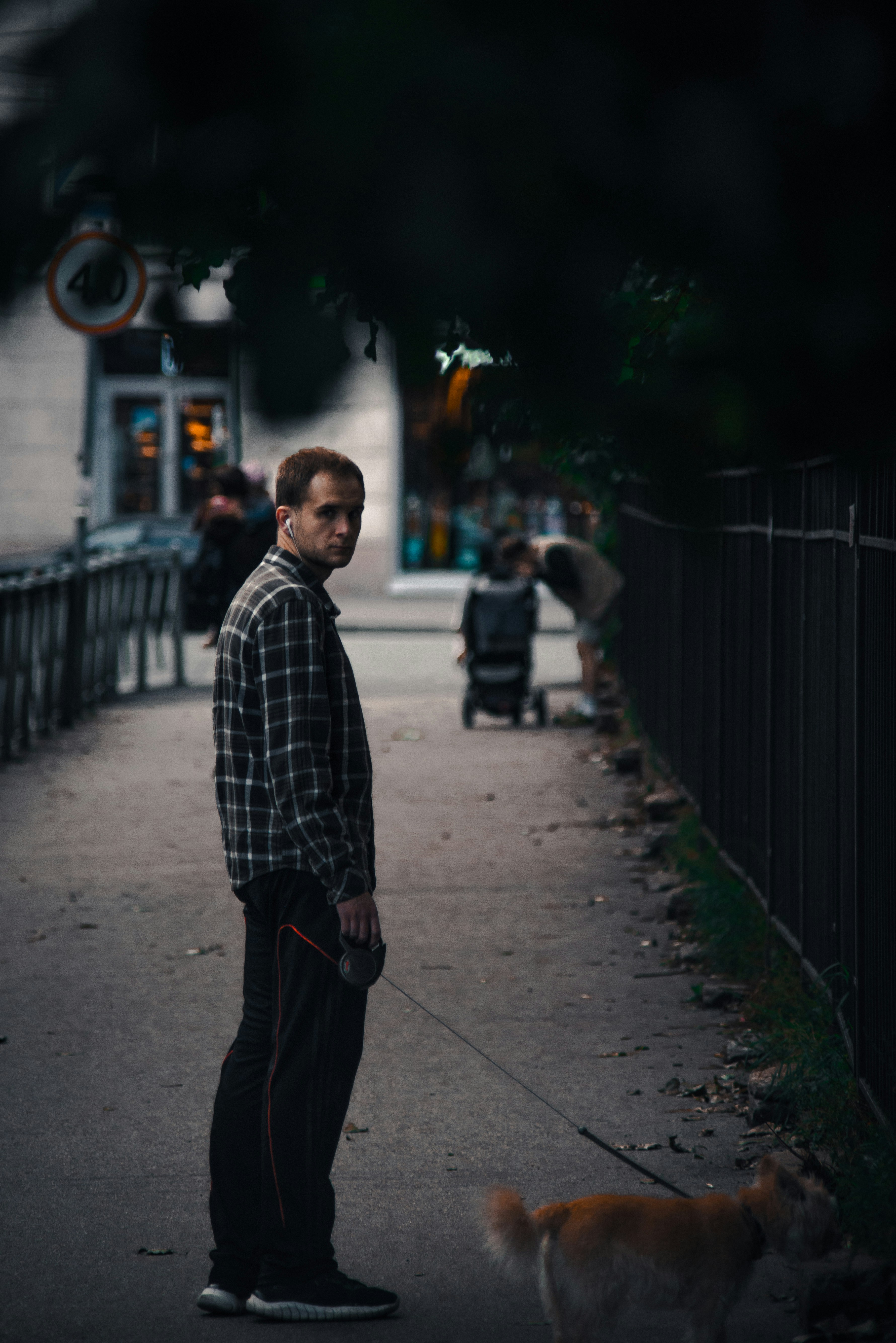 Man in a Plaid Shirt Awaits a Quiet Moment on the City Walk