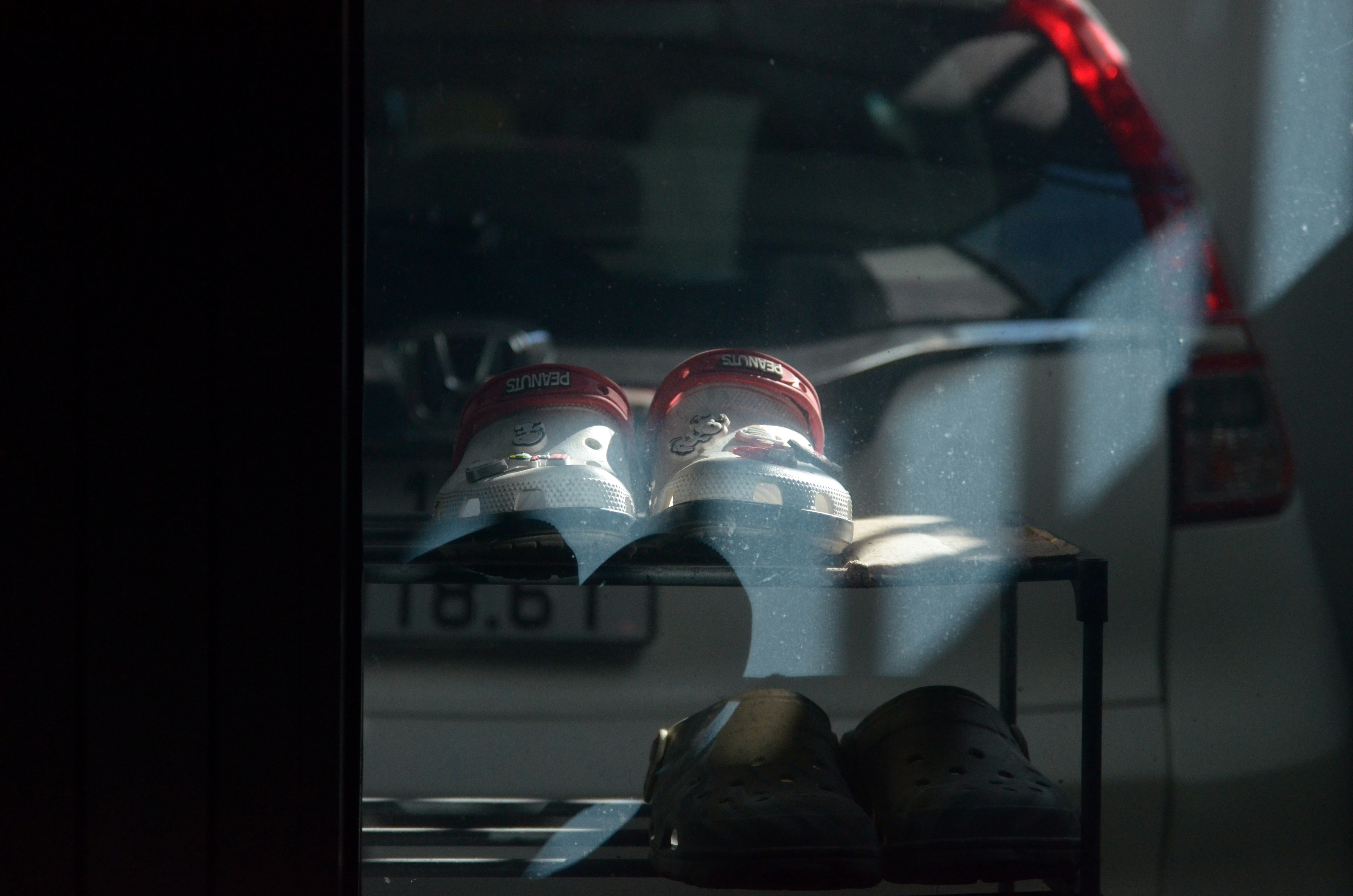 Sneakers on a Shelf, Reflected in a Car Window