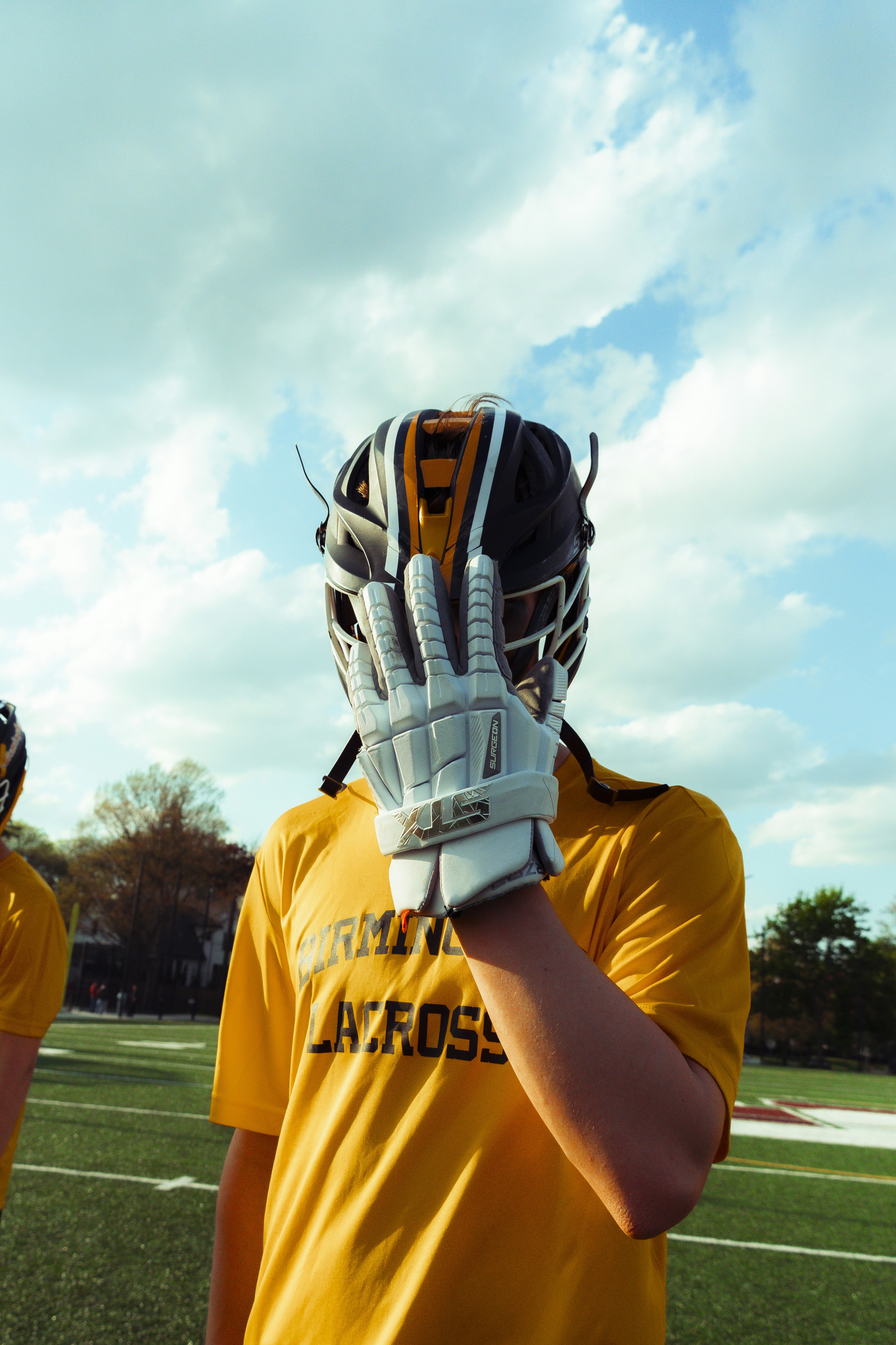 Grown-up gaze: a goalkeeper shields his face with gloves on a sunlit field